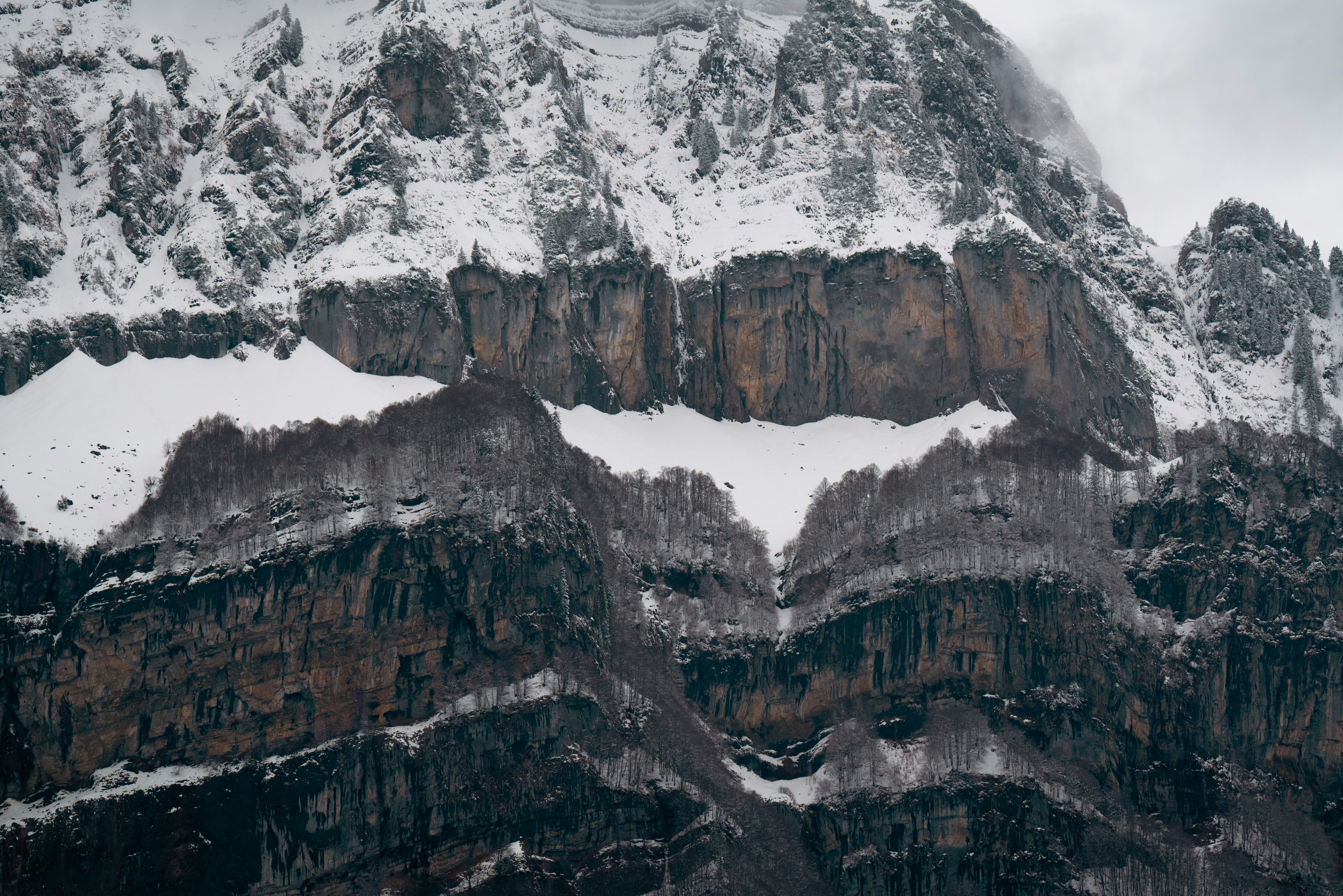 Snow-veiled Cliffs: Aroused Strata Above the Dark Basalt