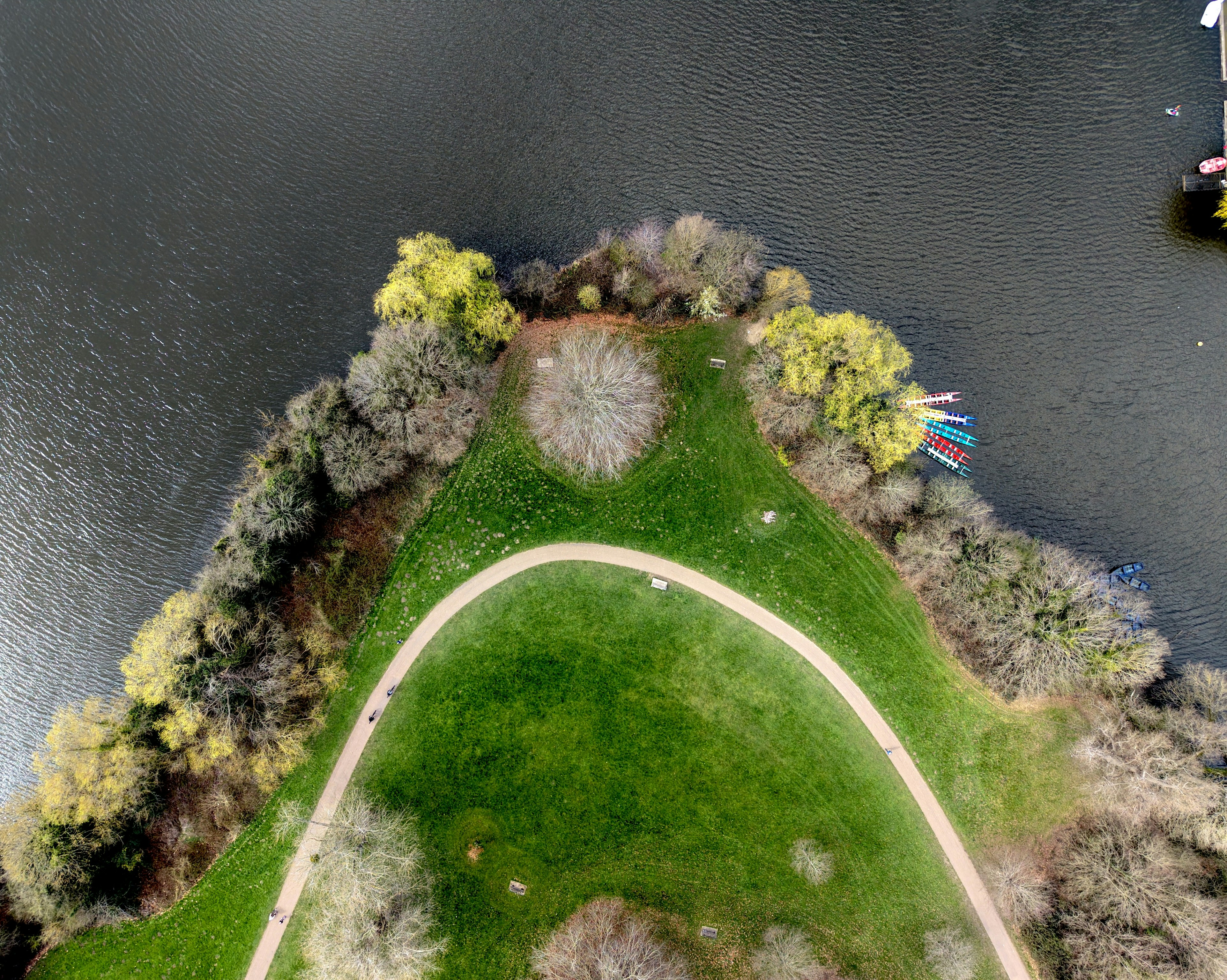Aerial Arc: Curving Path Framing a Green Island in Calm Waters