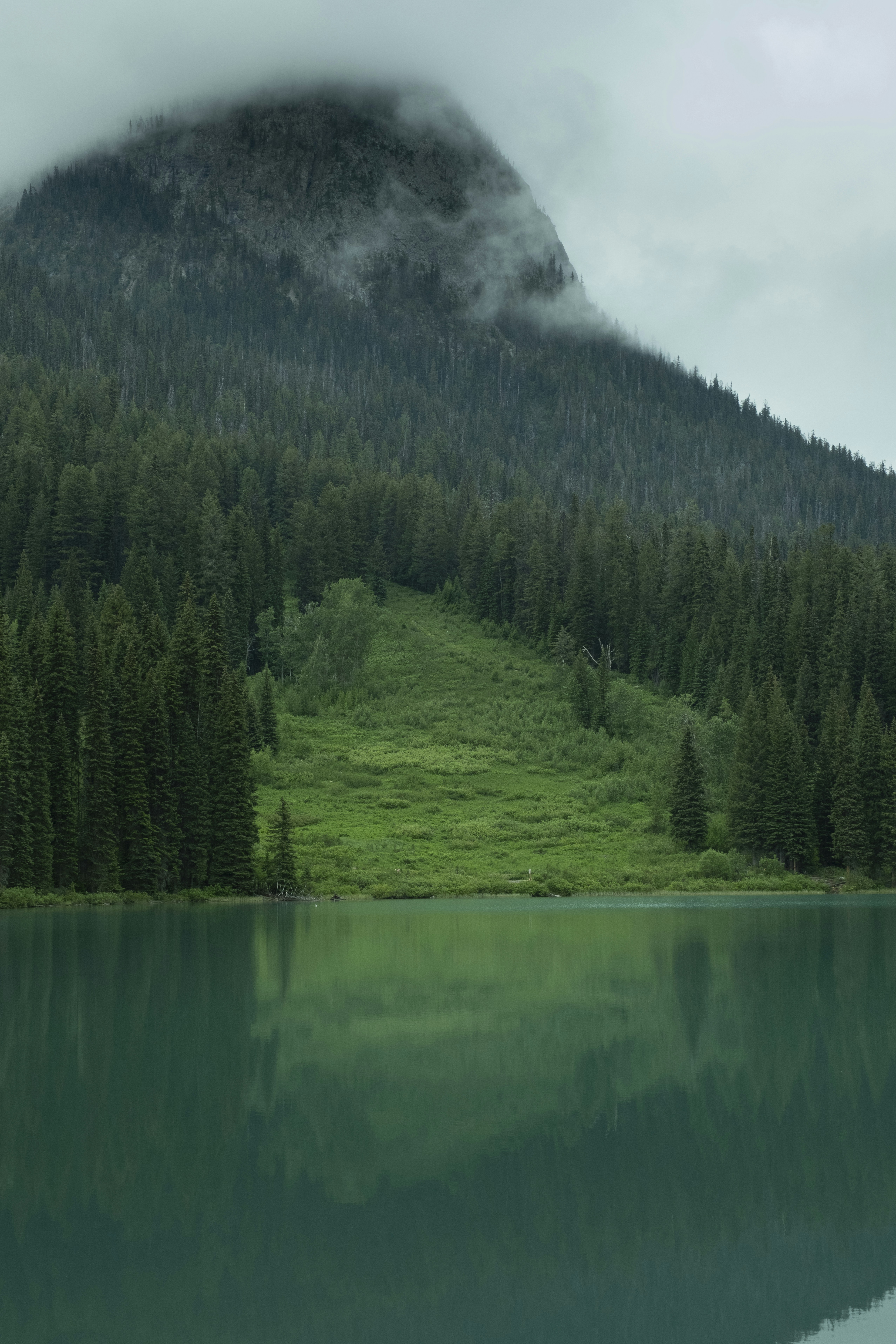 Mist-Clad Peak Over a Serene Alpine Lake