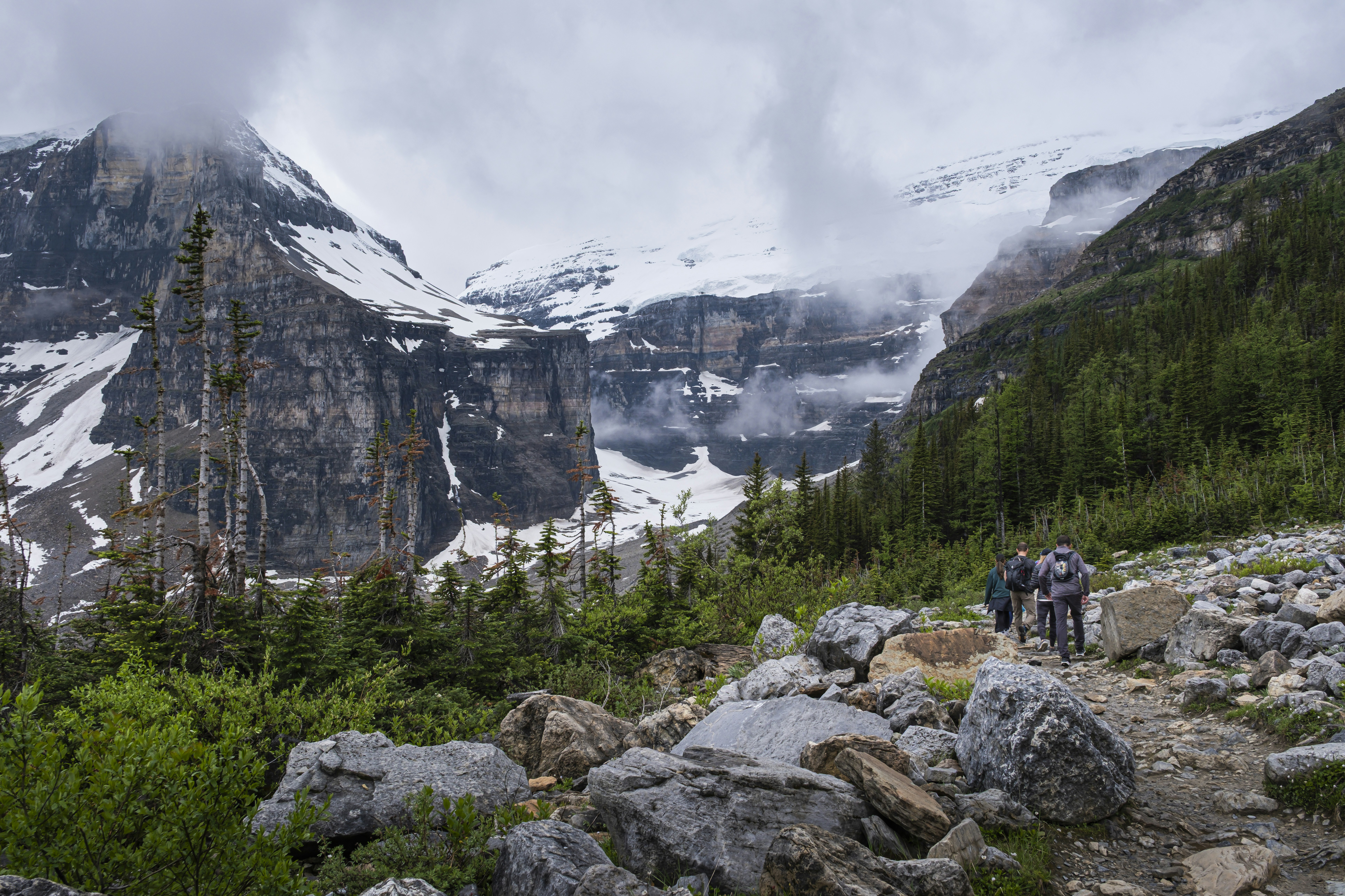 Hikers Trek Through Alpine Rim Beneath Snow-Capped Peaks