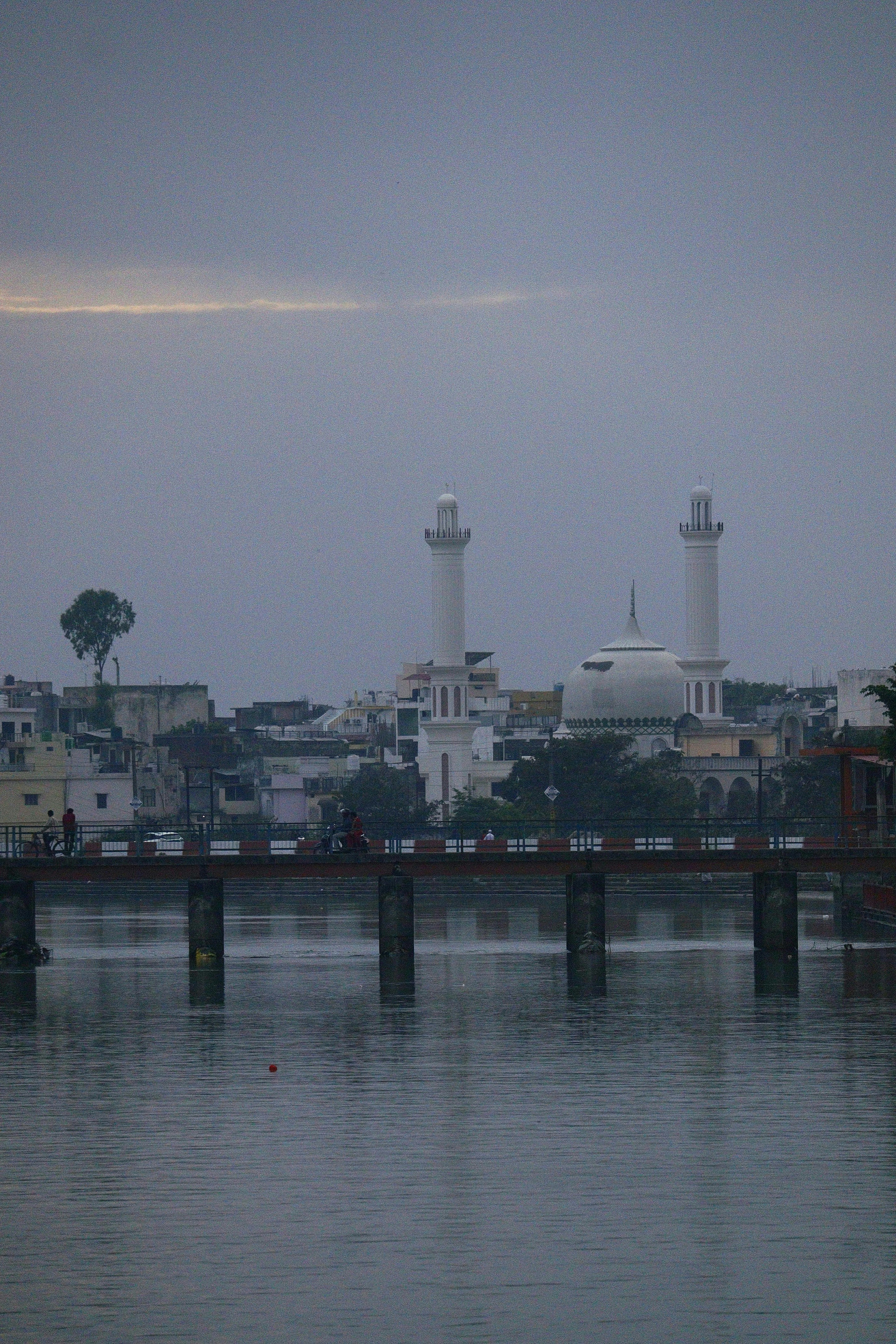 Mosque and skyline across a quiet river at dusk