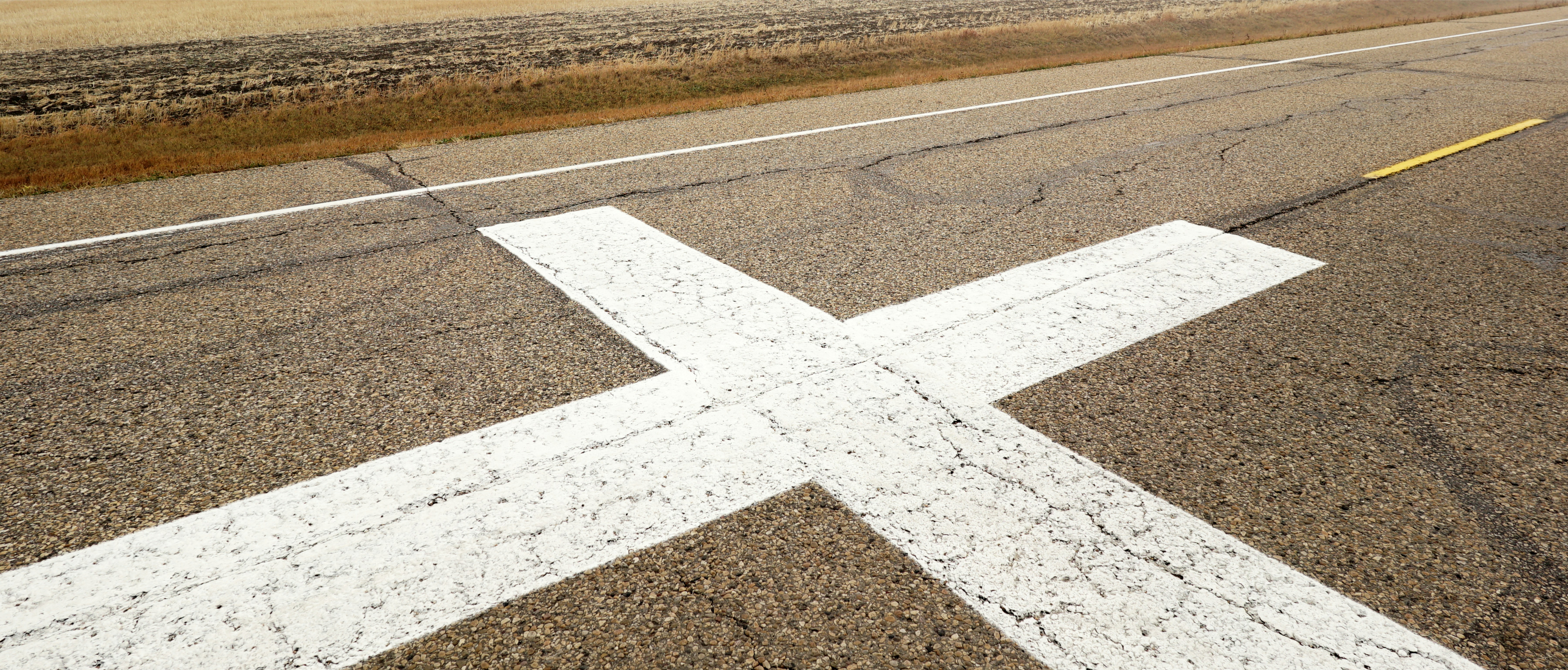 Crossroads of Color: A Weathered X Across the Asphalt Horizon