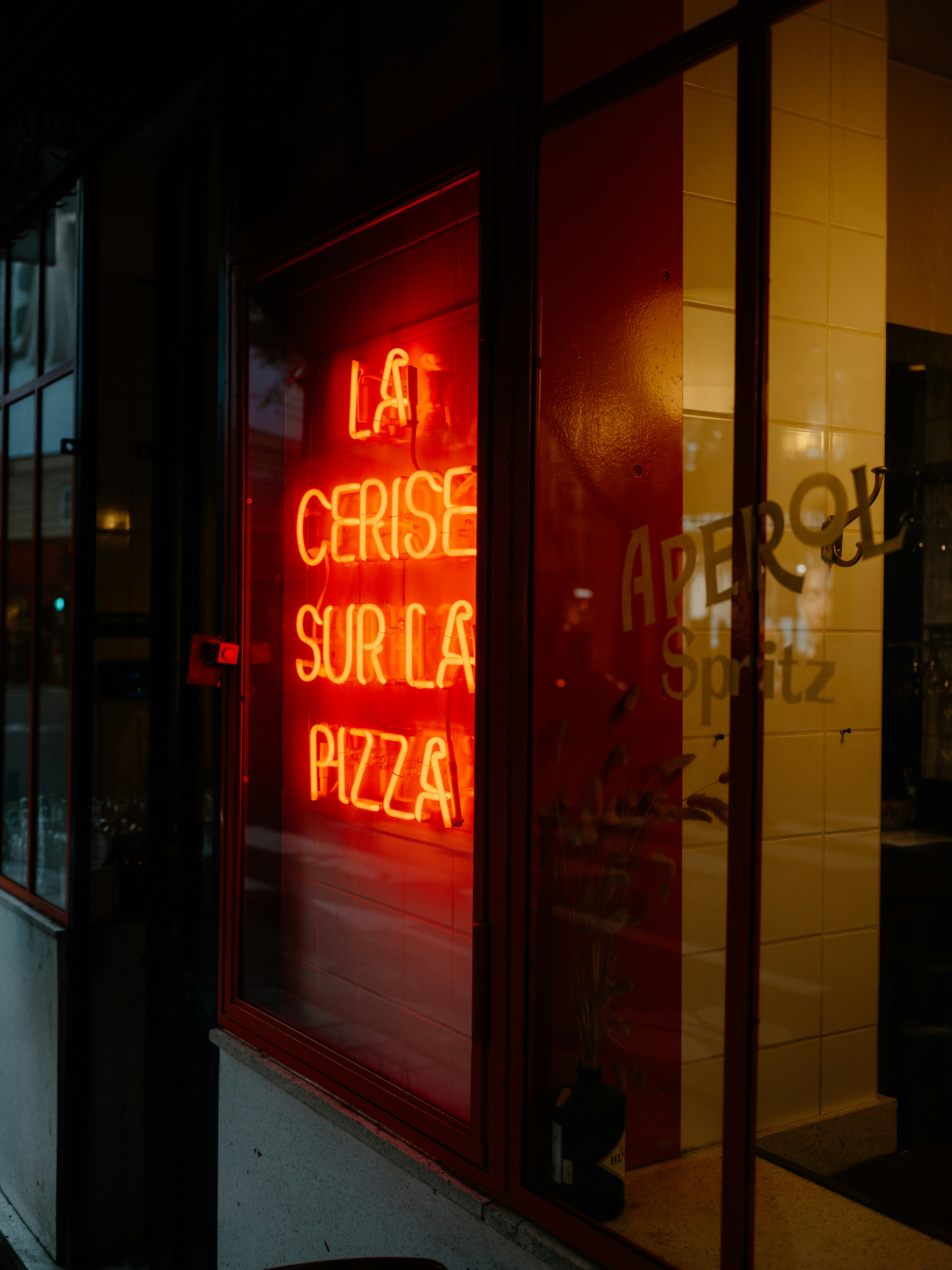 Neon Lure: Red Pizza Sign Reflected in Glass