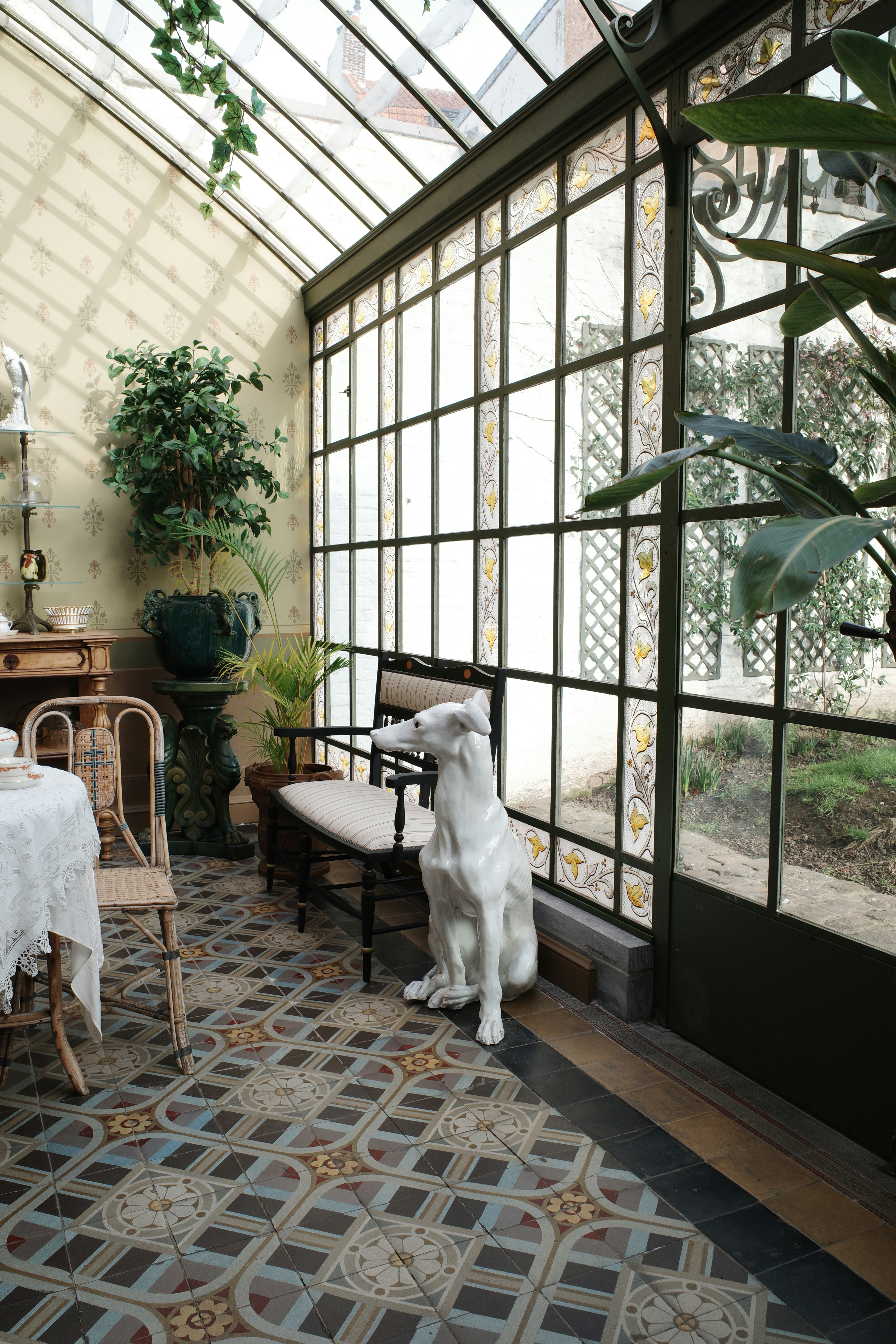 White statue of a dog beside a vintage greenhouse nook