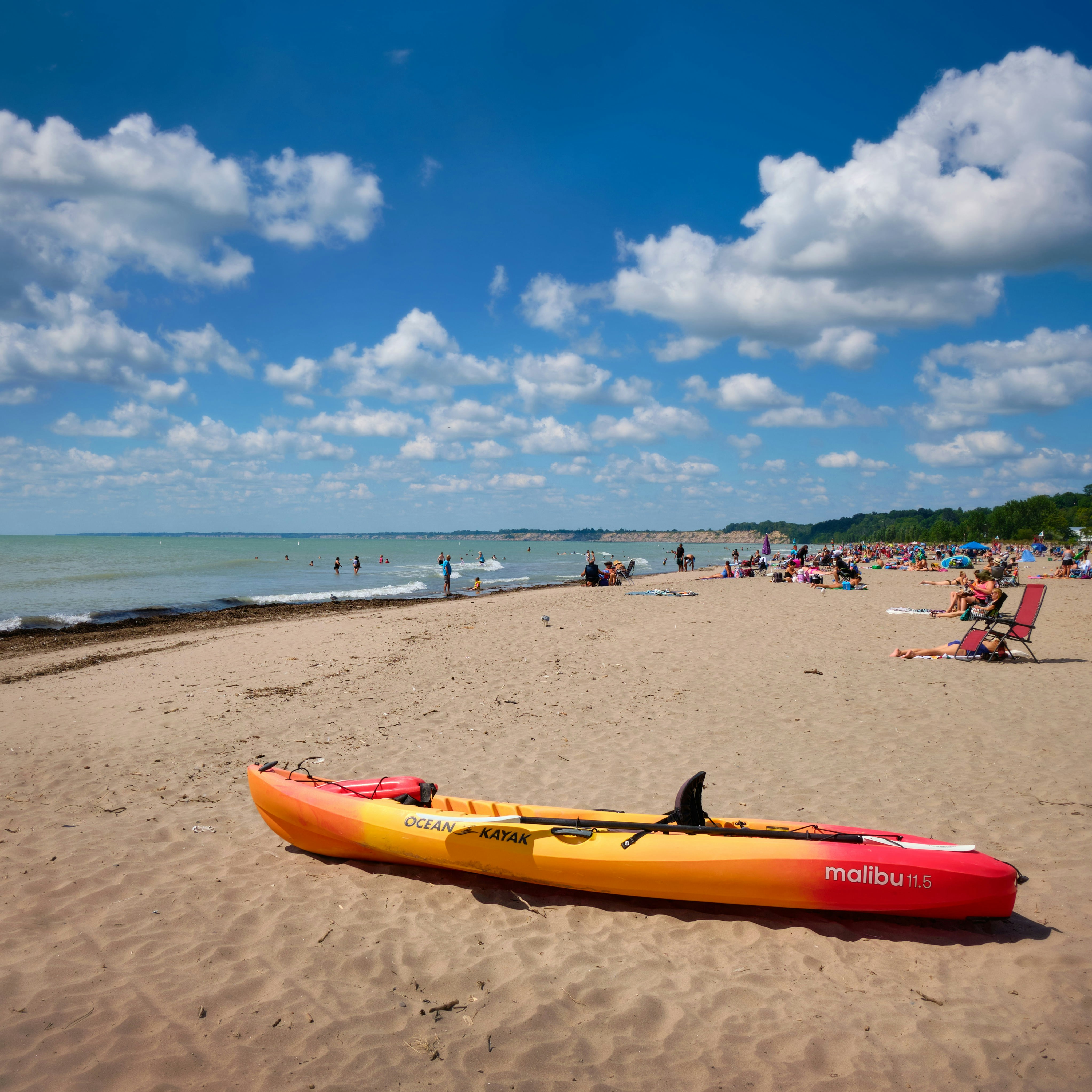 Sunlit Kayak and Crowd on a Dune-Outlined Beach