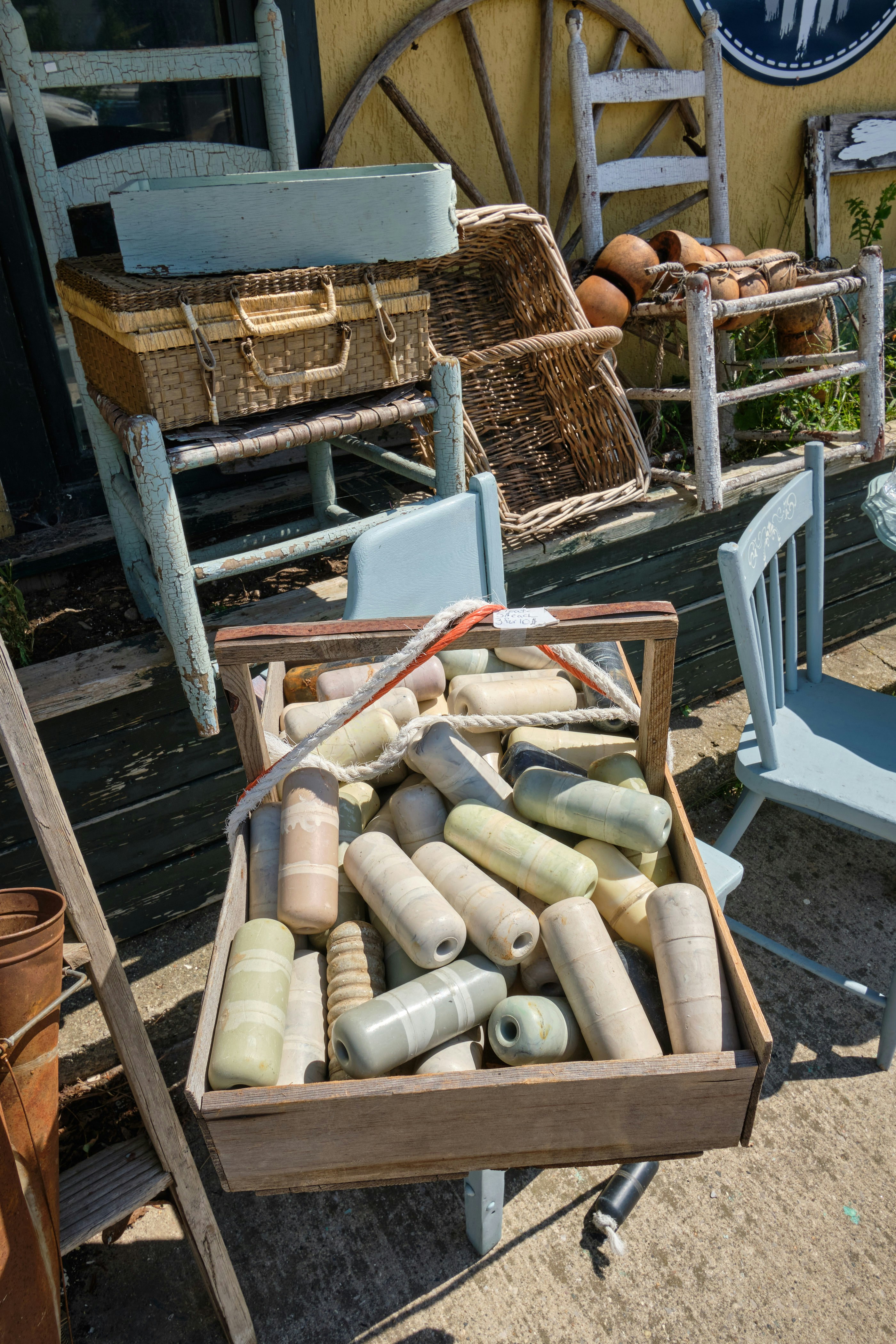 Vintage Market Still-Life: Bottles in a Wooden Crate Amid Weathered Chairs