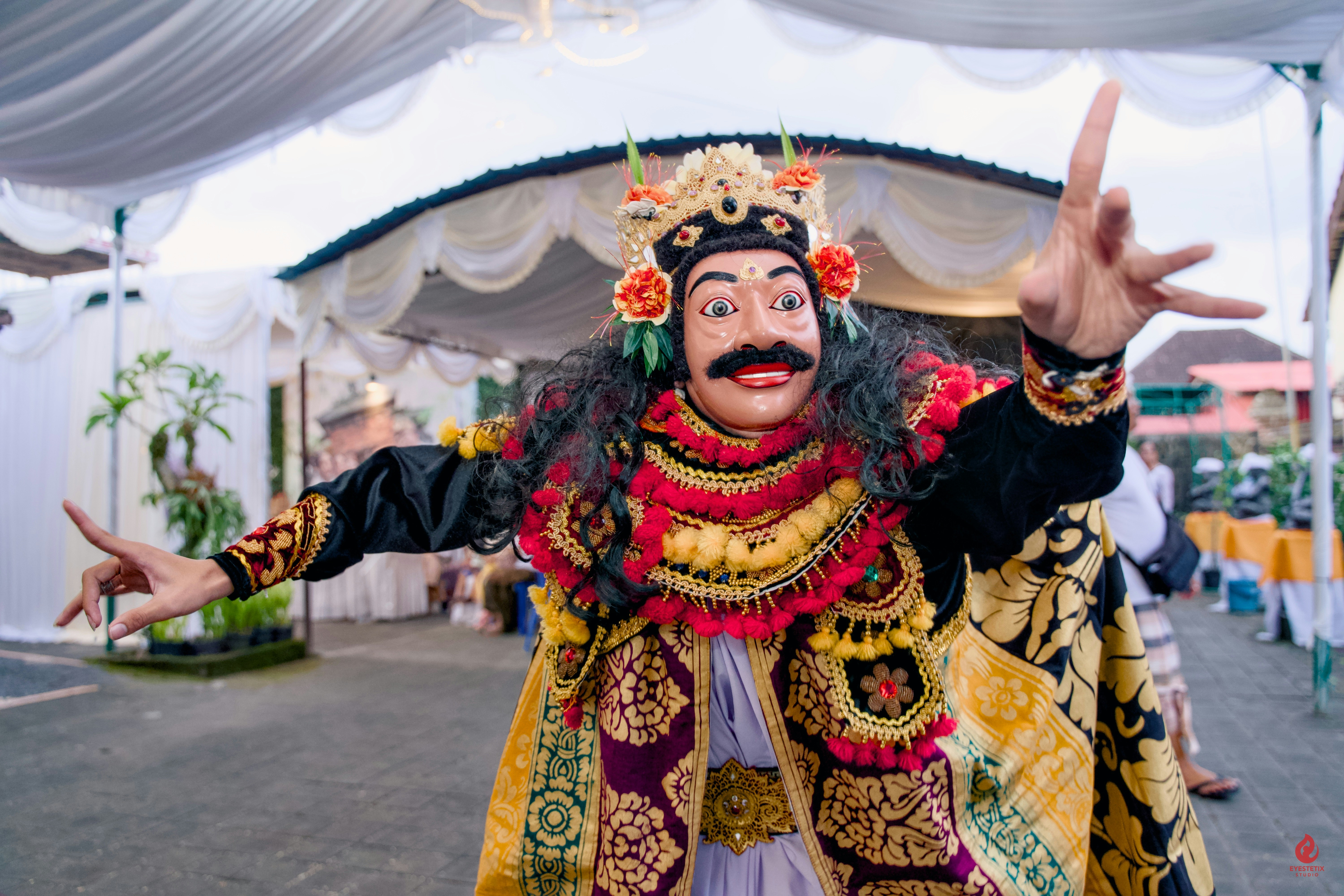 Masked Magician in Full Parade Regalia Reaches Forward