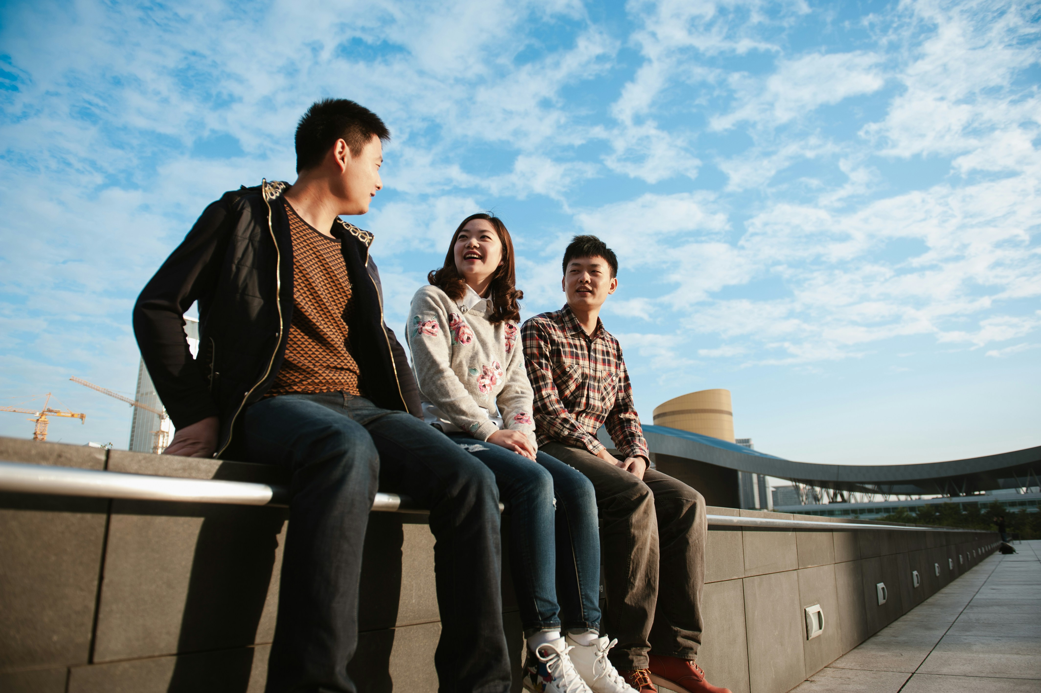 Three Friends on a Riverside Terrace Under a Bright Sky