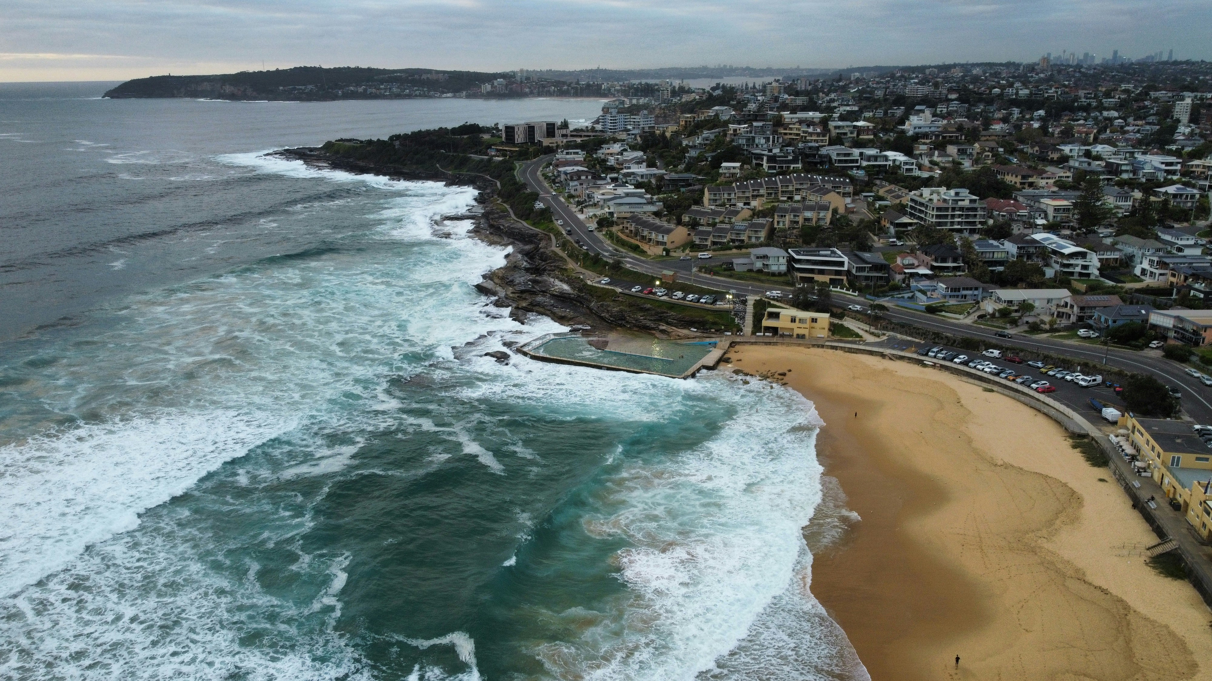 Coastal Cliffside Town Unfolding Along a Curved Golden Beach