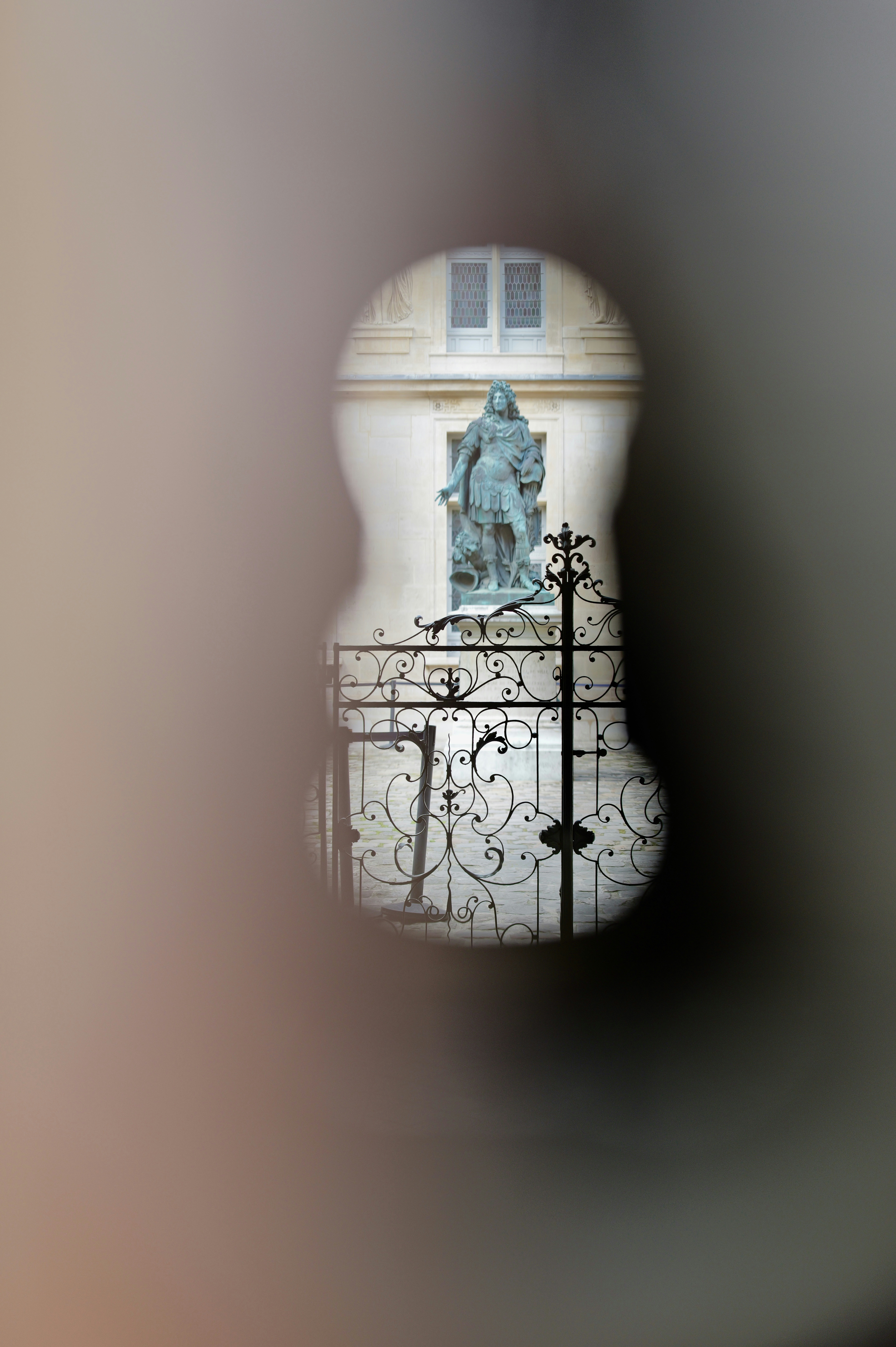 Through the Gate: A Statue Framed by Arching Shadows