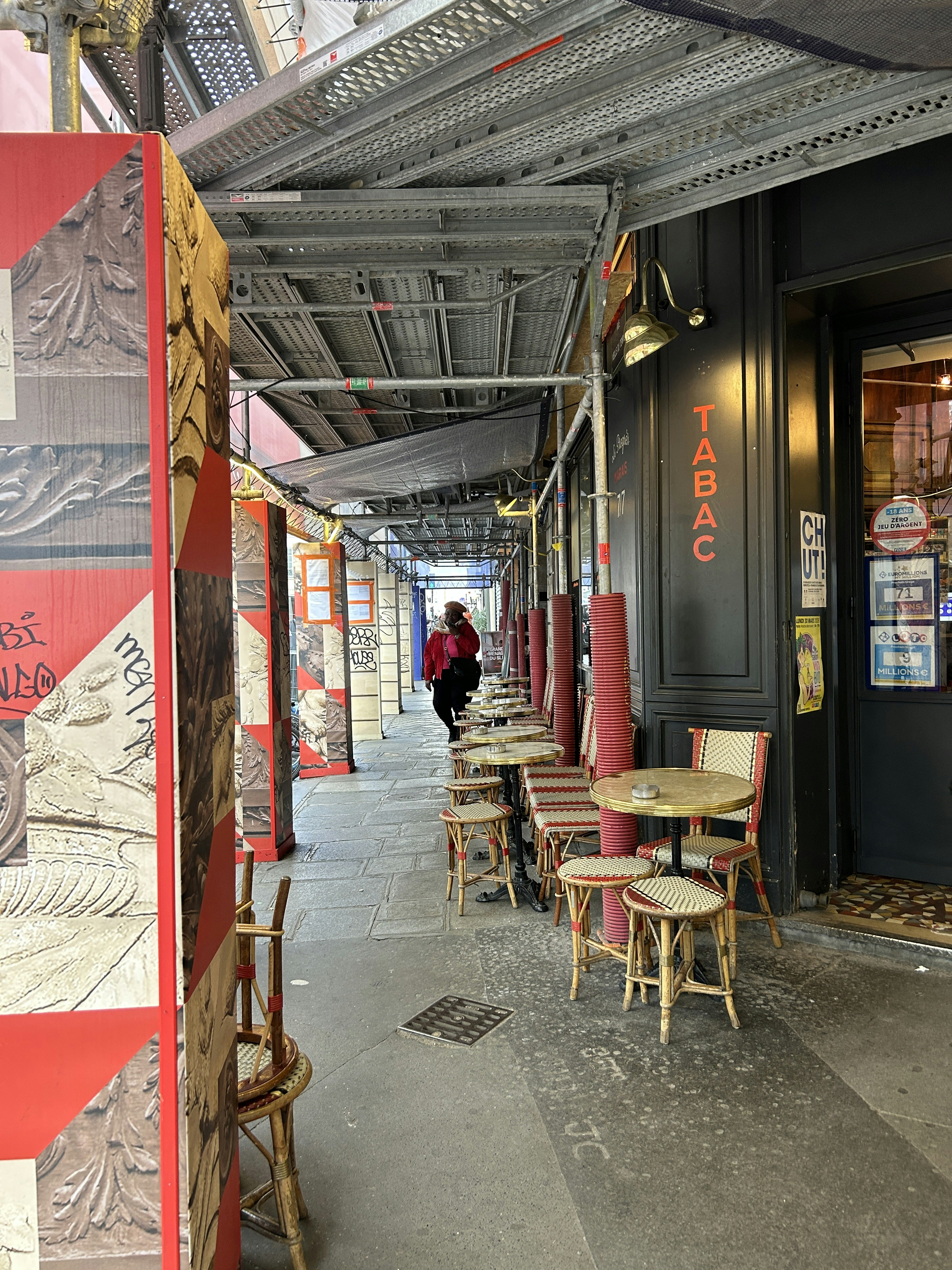 Street-side Café Under Construction: Chairs, Shadows, and Red-Accent Panels