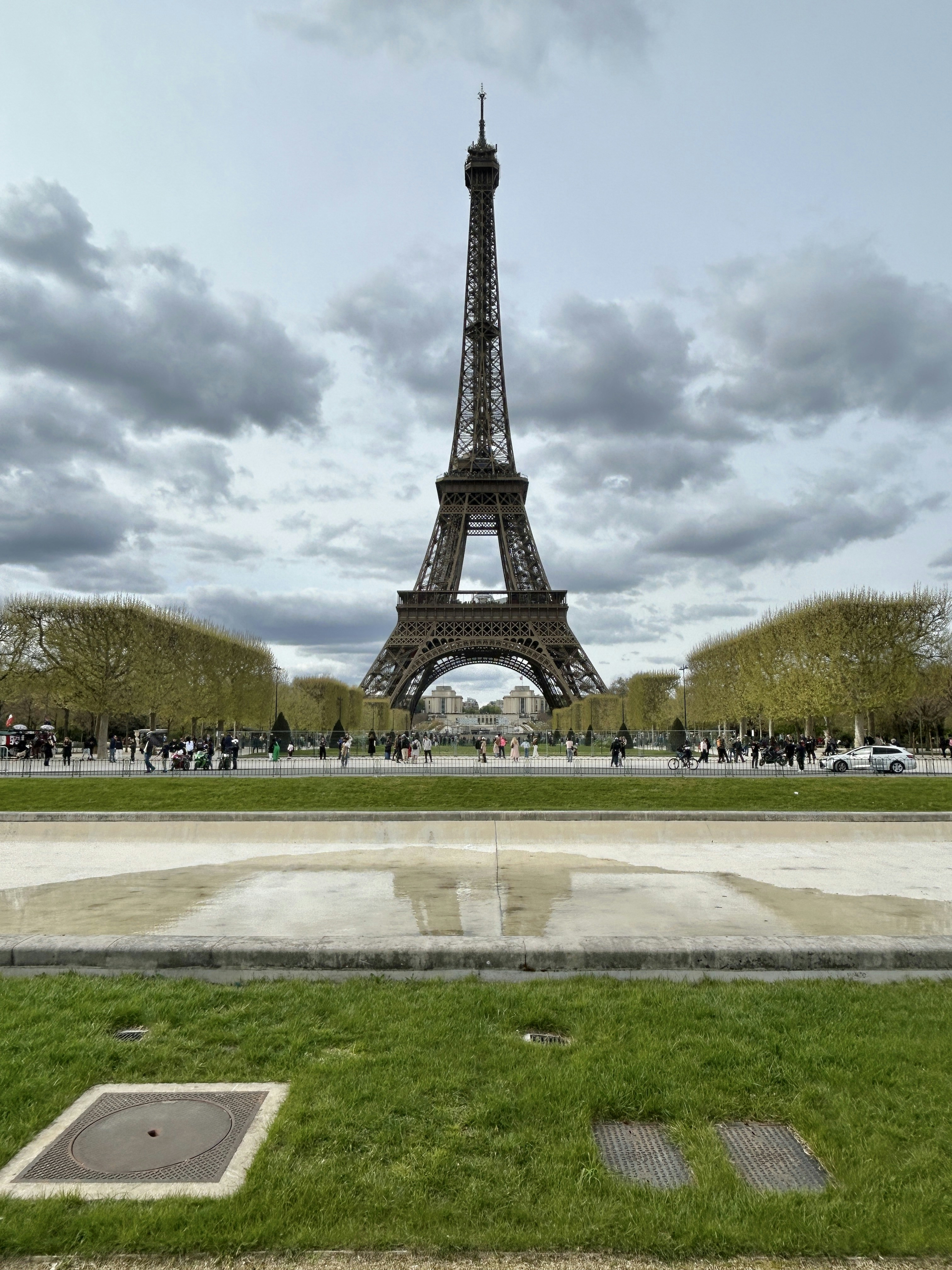Centered Iron Giant: The Eiffel Tower Framed by a Park of Daylight Clouds