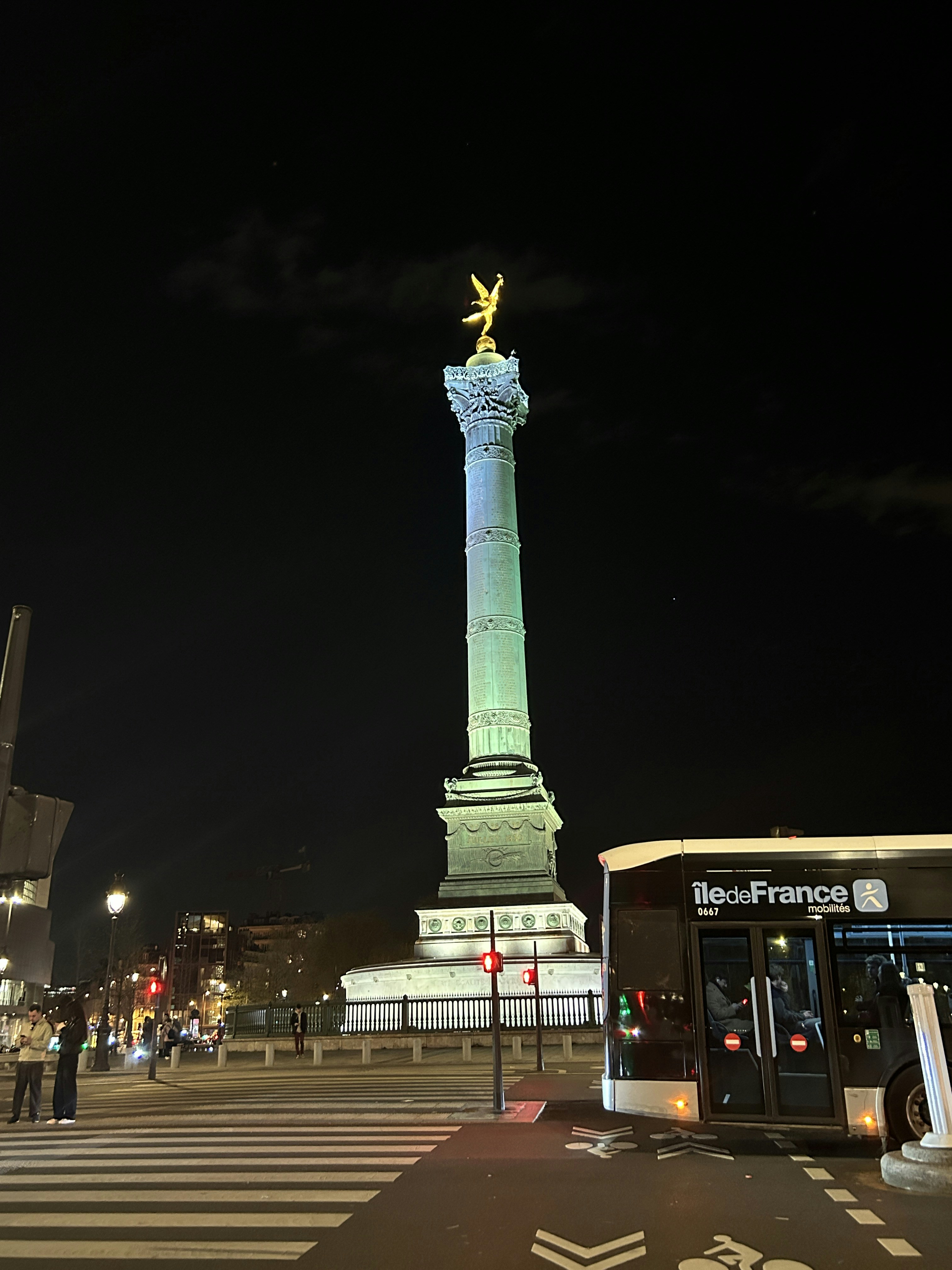 Nighttime Triumph: The Golden Statue Rising Above the Avenue