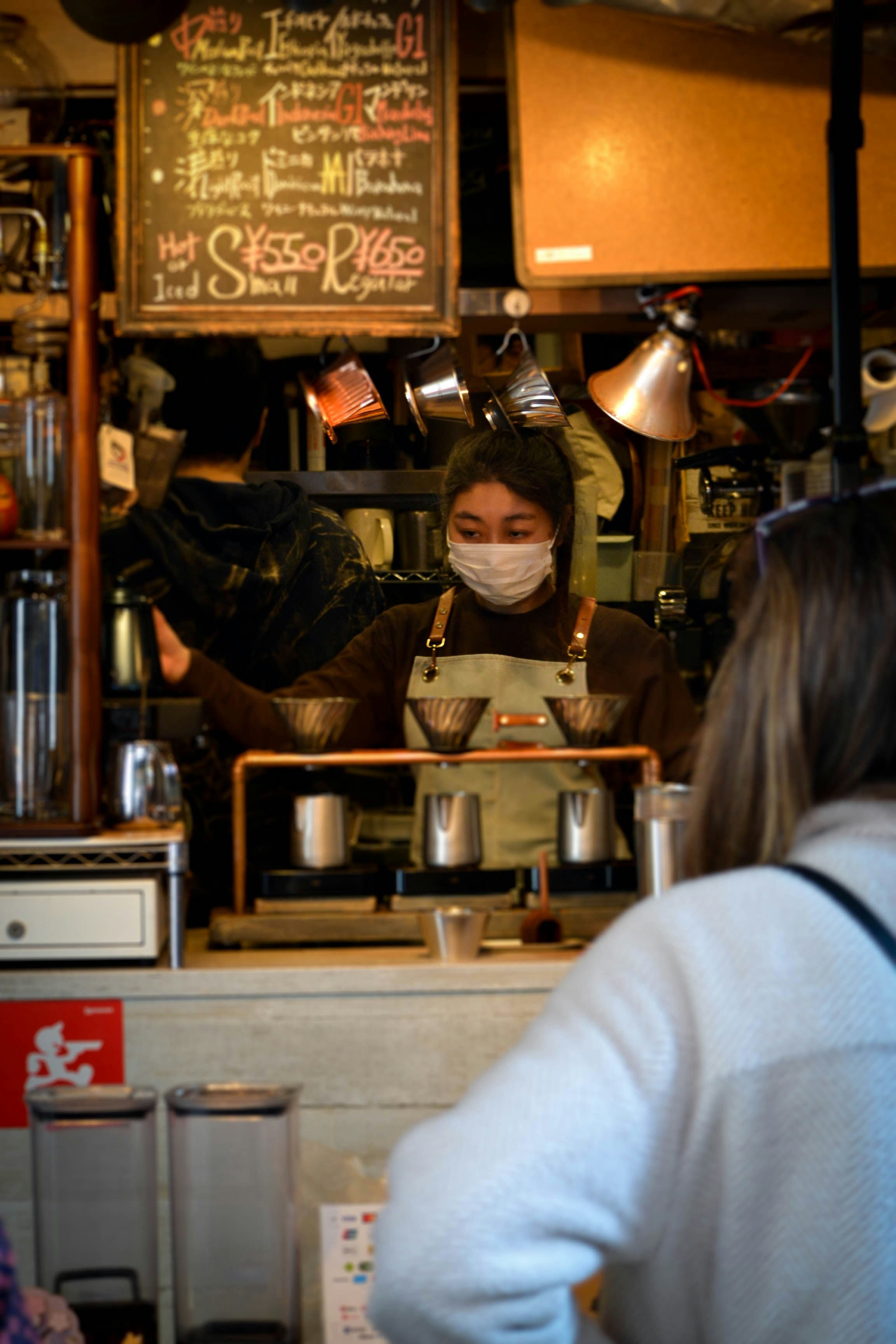 Masked Barista Behind the Counter in a Warm Café