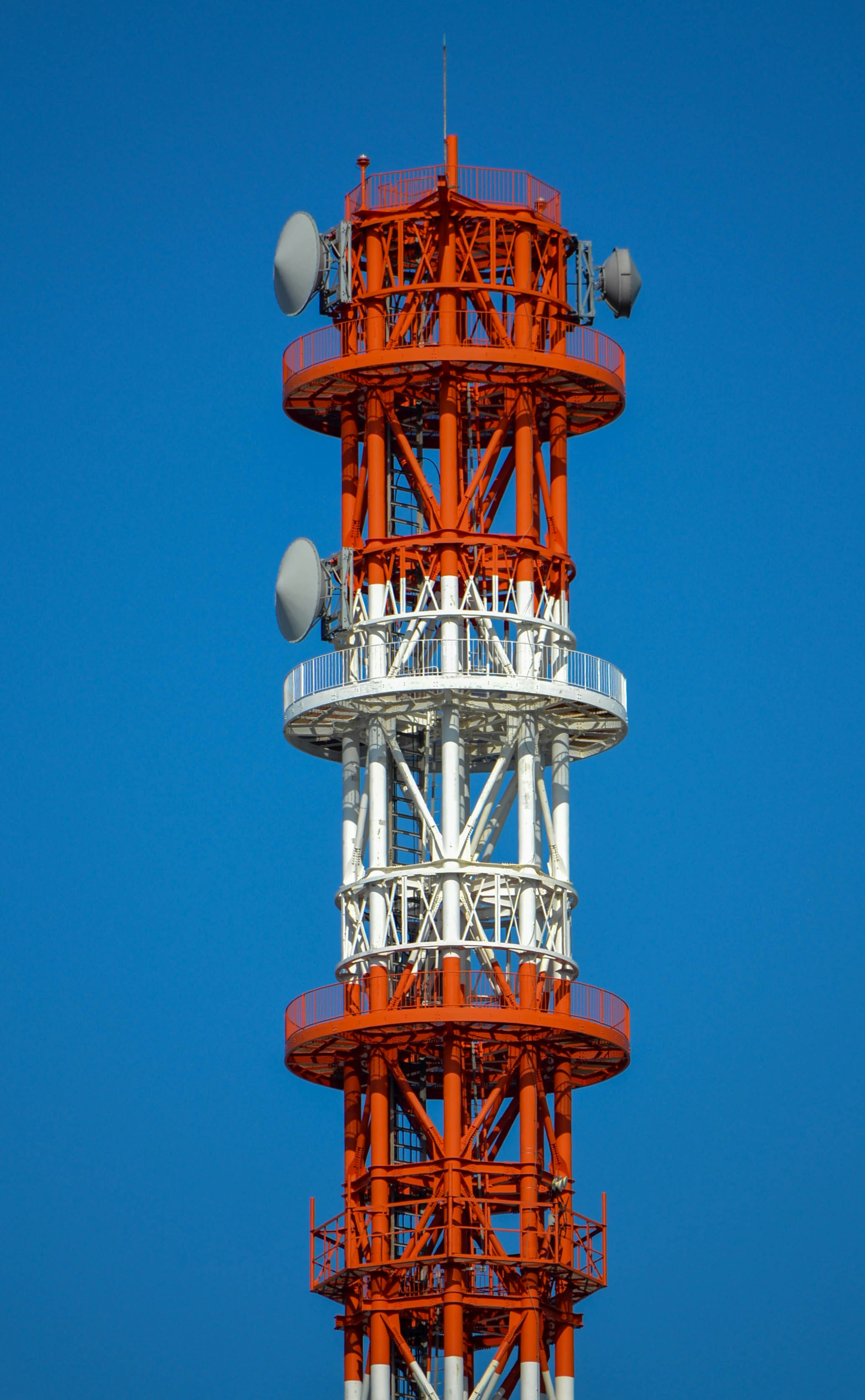 Red-and-White Communications Tower Reaching Toward a Clear Blue Sky
