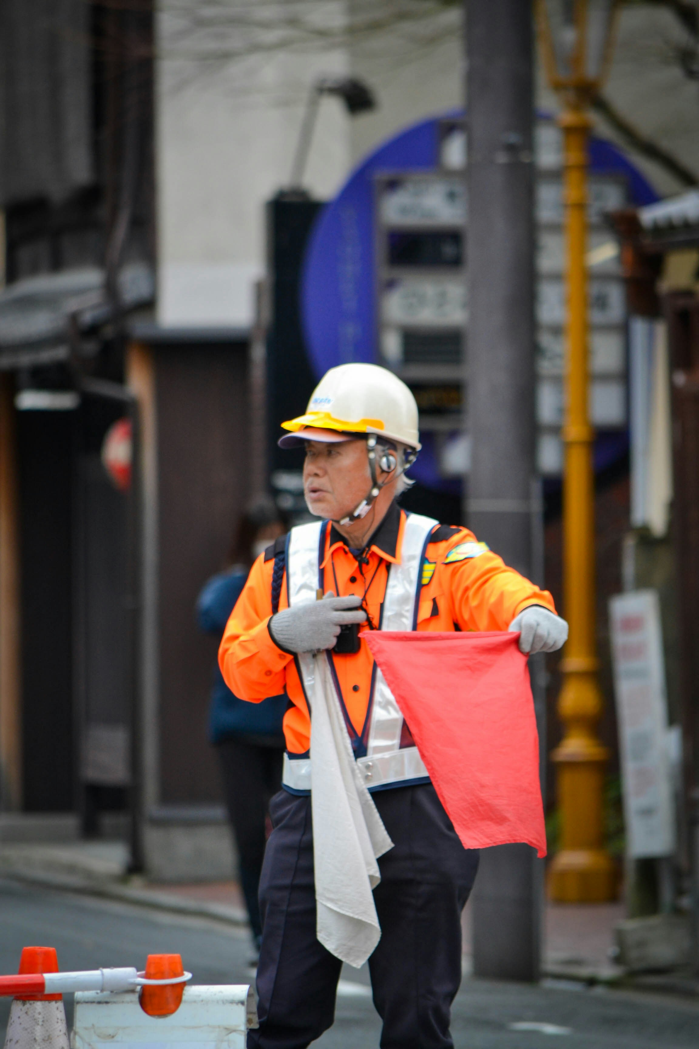 Orange-Clad Worker with Red Flag in Urban Work Zone