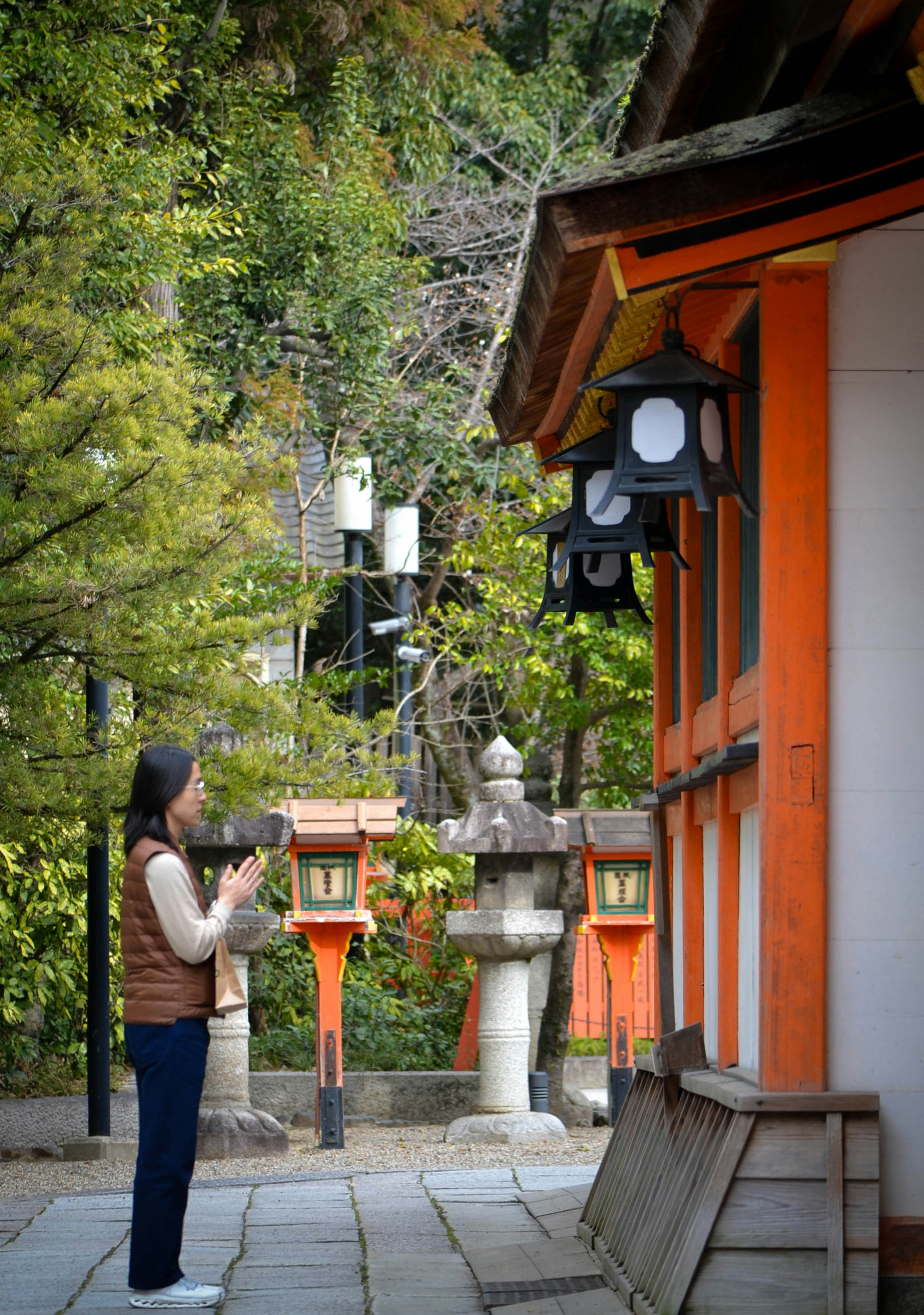 Temple Courtyard Stillness: A Woman in Prayer Beside the Lanterns