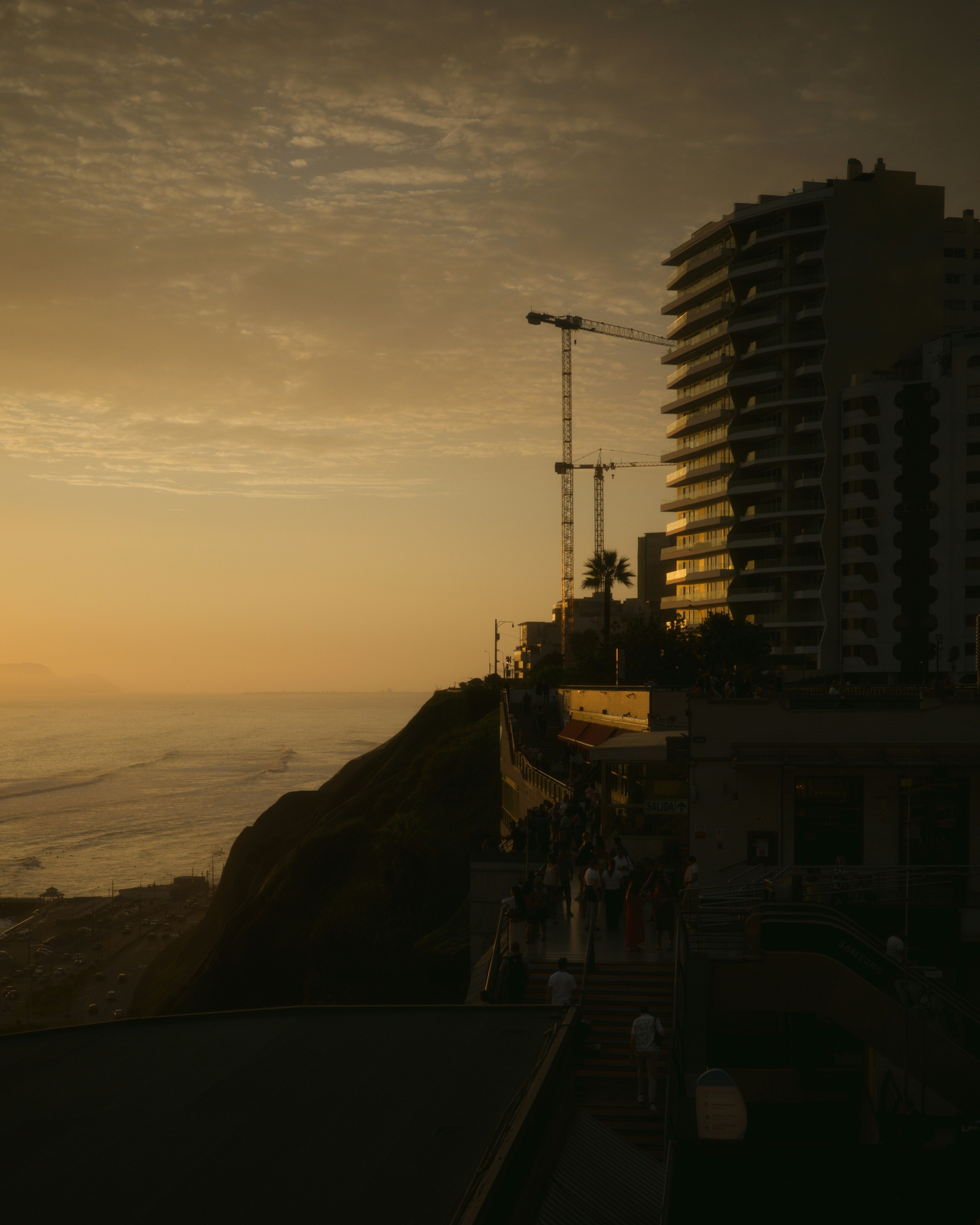 Sunset Over the Cliffside: Construction Lights and Shadowed High-Rise