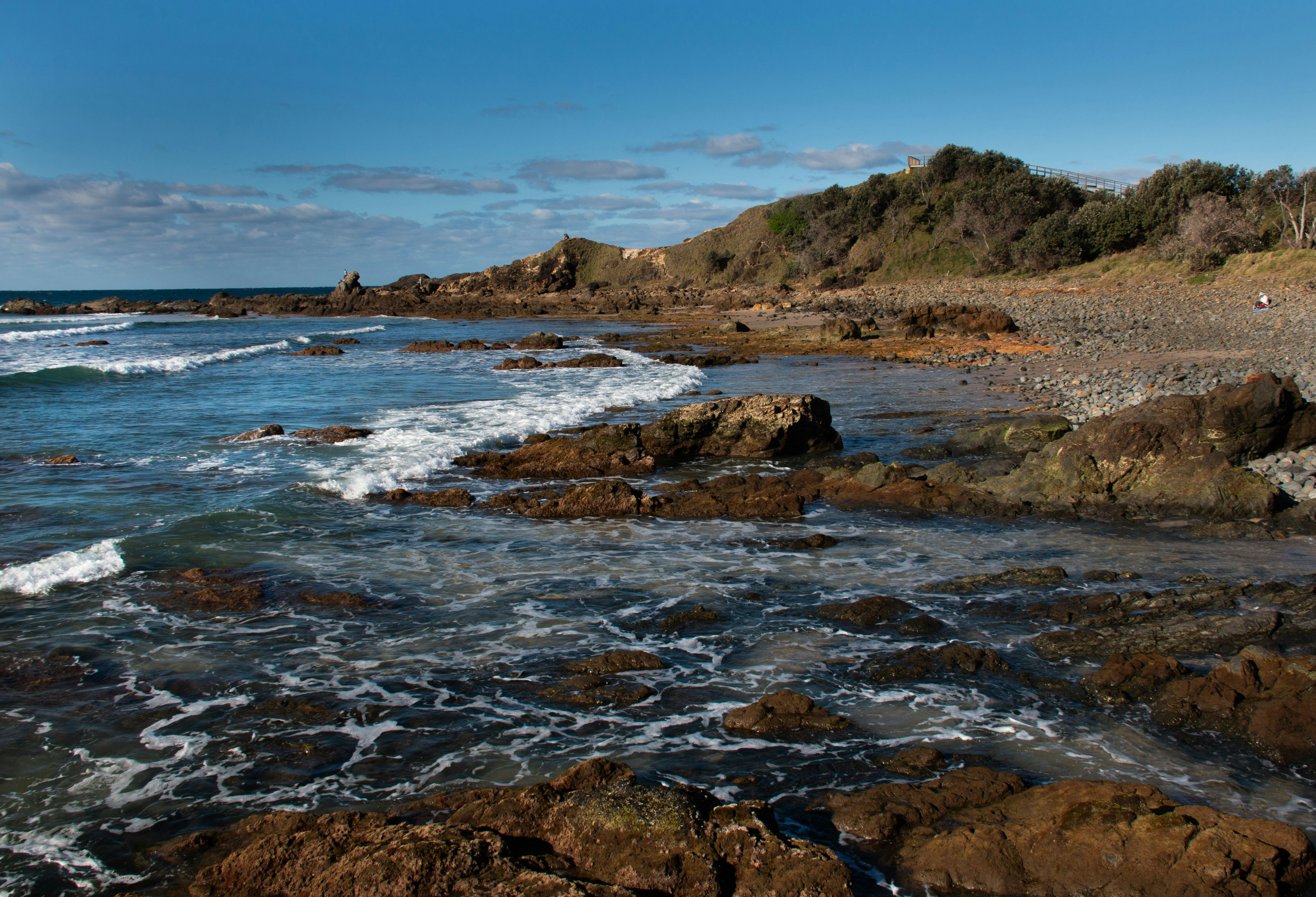 Rugged shoreline beneath a blue sky with sunlit rockscape