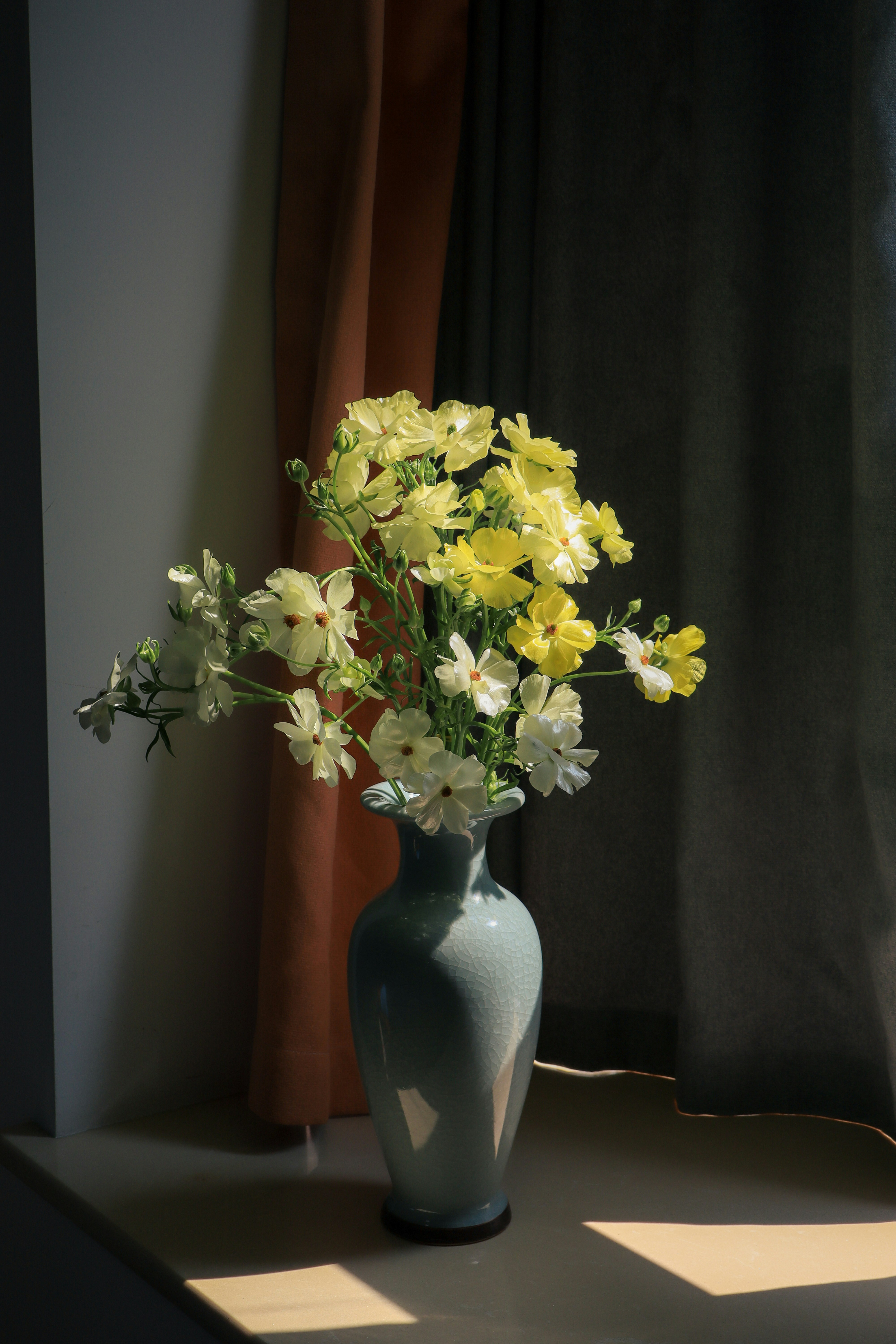 Vase of Yellow and White Blossoms on a Sunlit Windowsill