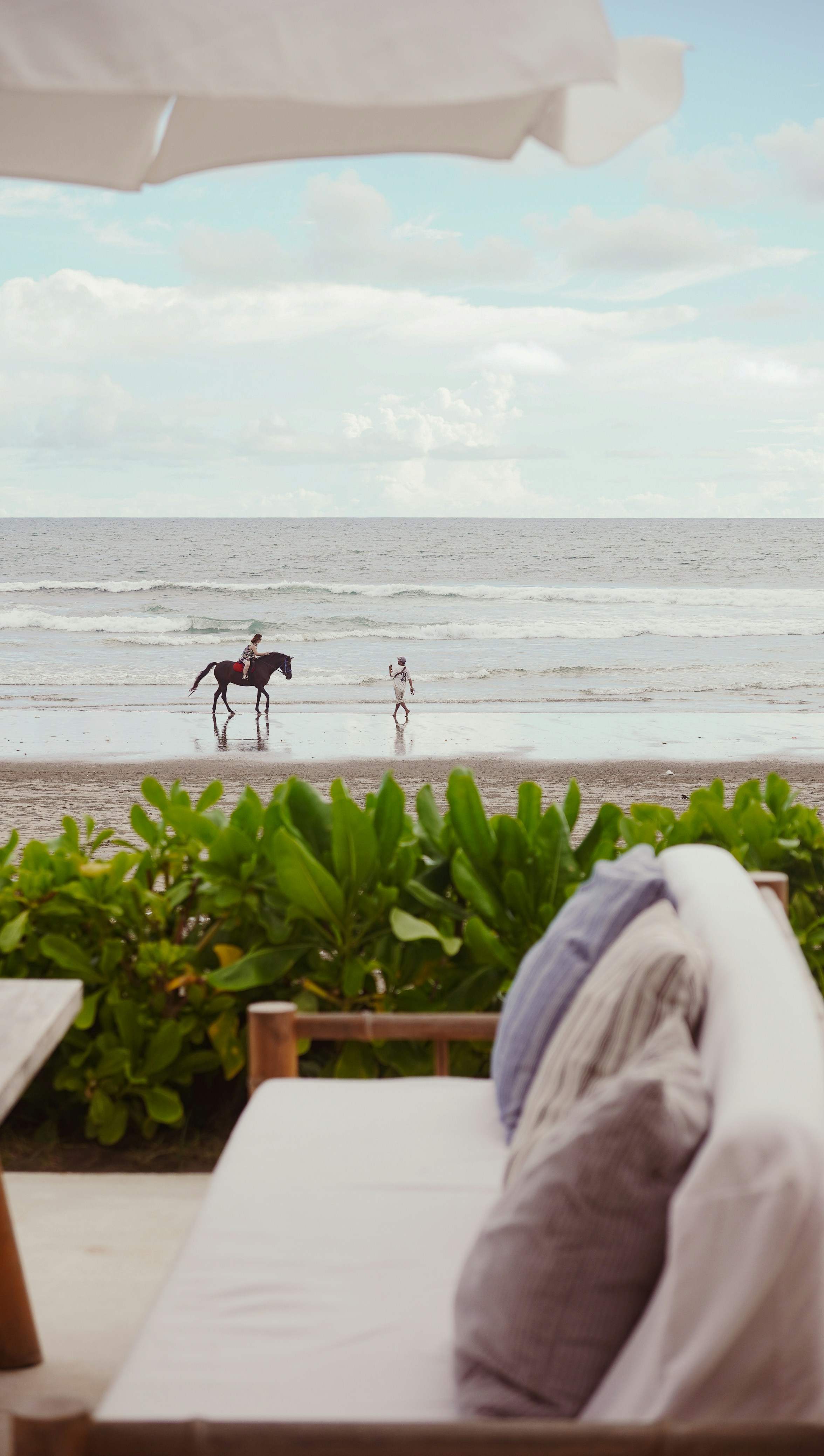 Beachside Calm: A Rider and a Jogger Beneath Sea-Sky Light