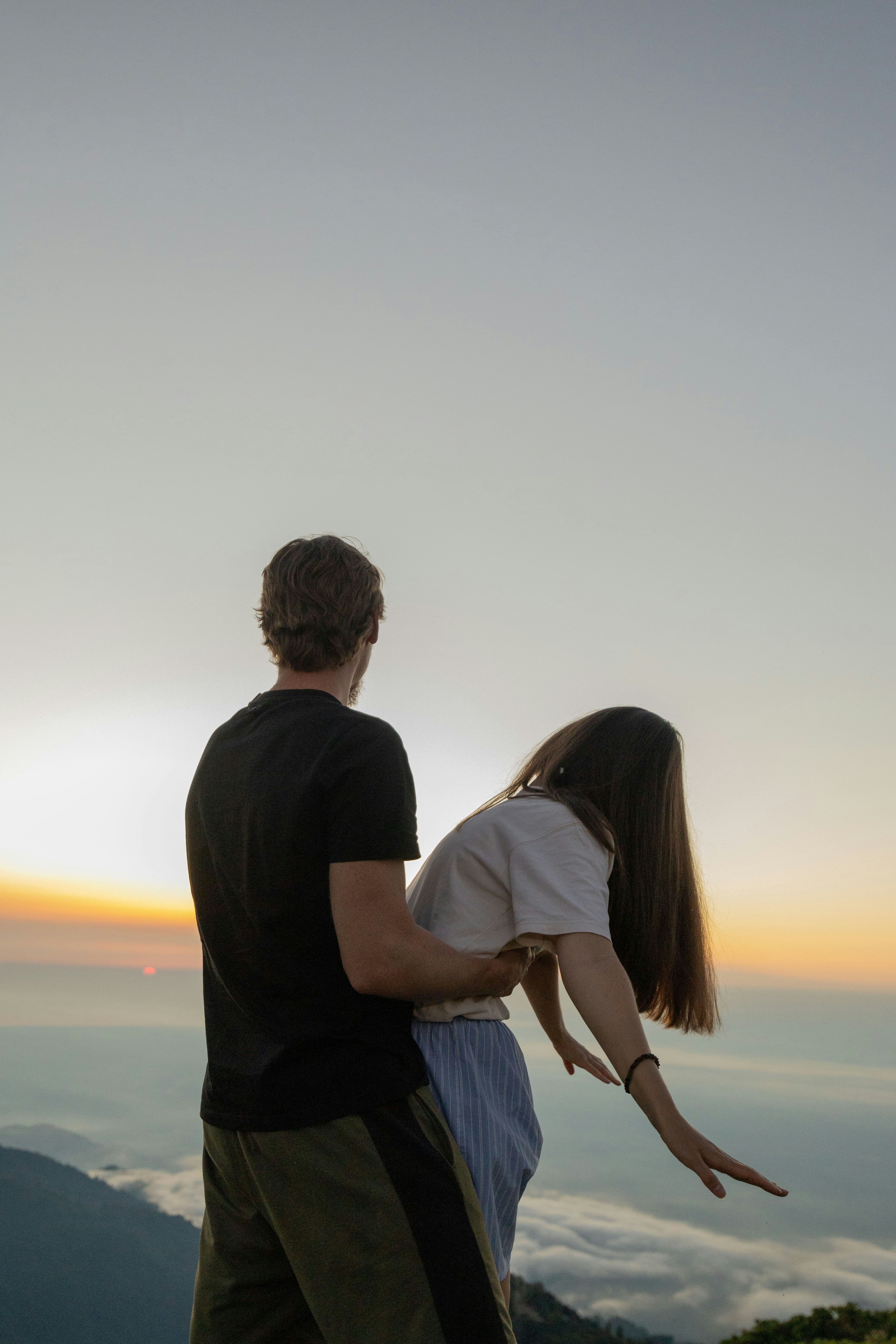 Two explorers at edge of light: a couple facing a distant horizon