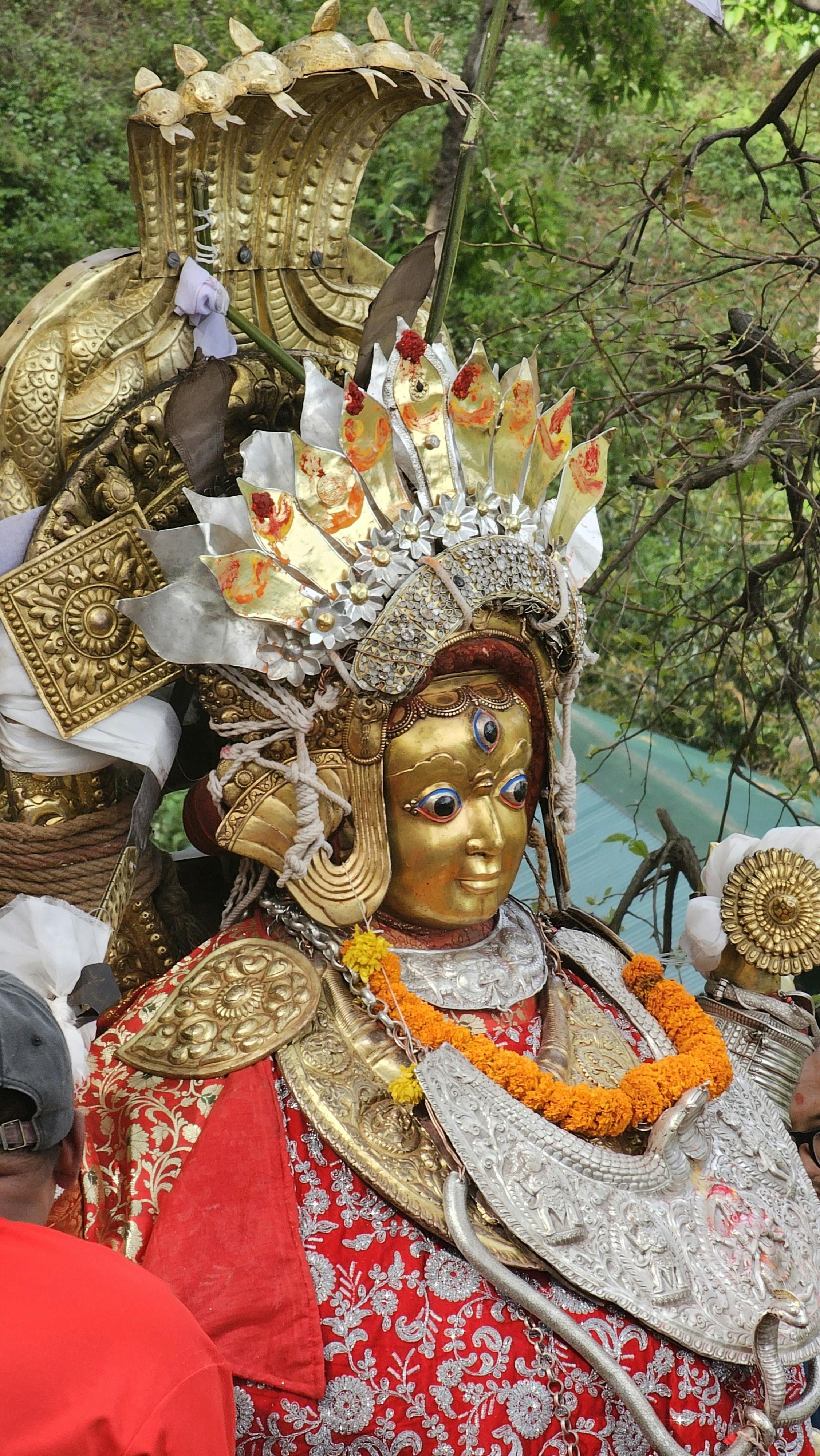 Golden Statue of a Sacred Figure Adorned with Ornate Headdress and Garlands