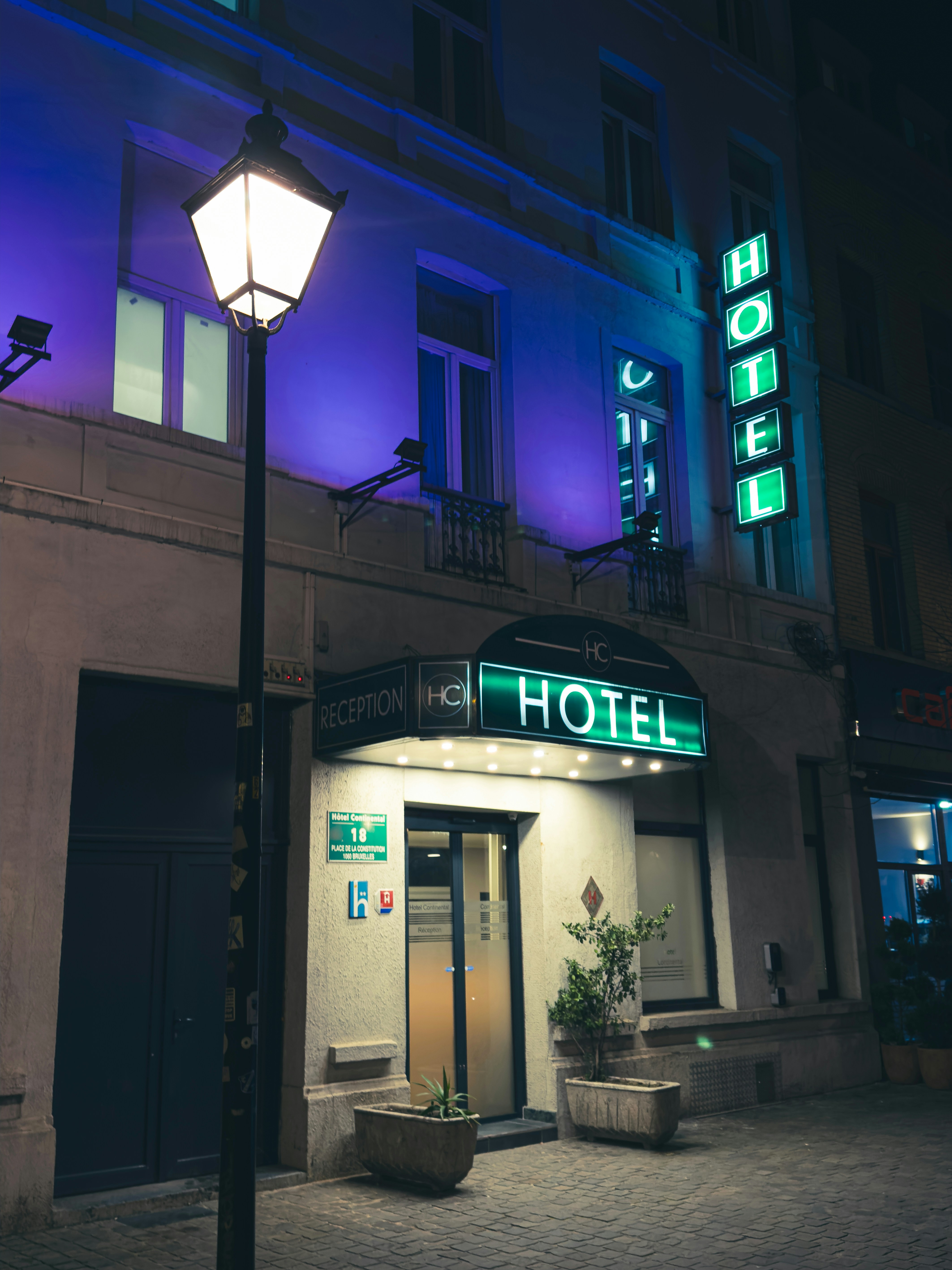 Neon Hotel at Night: A Quiet Welcome by the Cobblestone Entrance