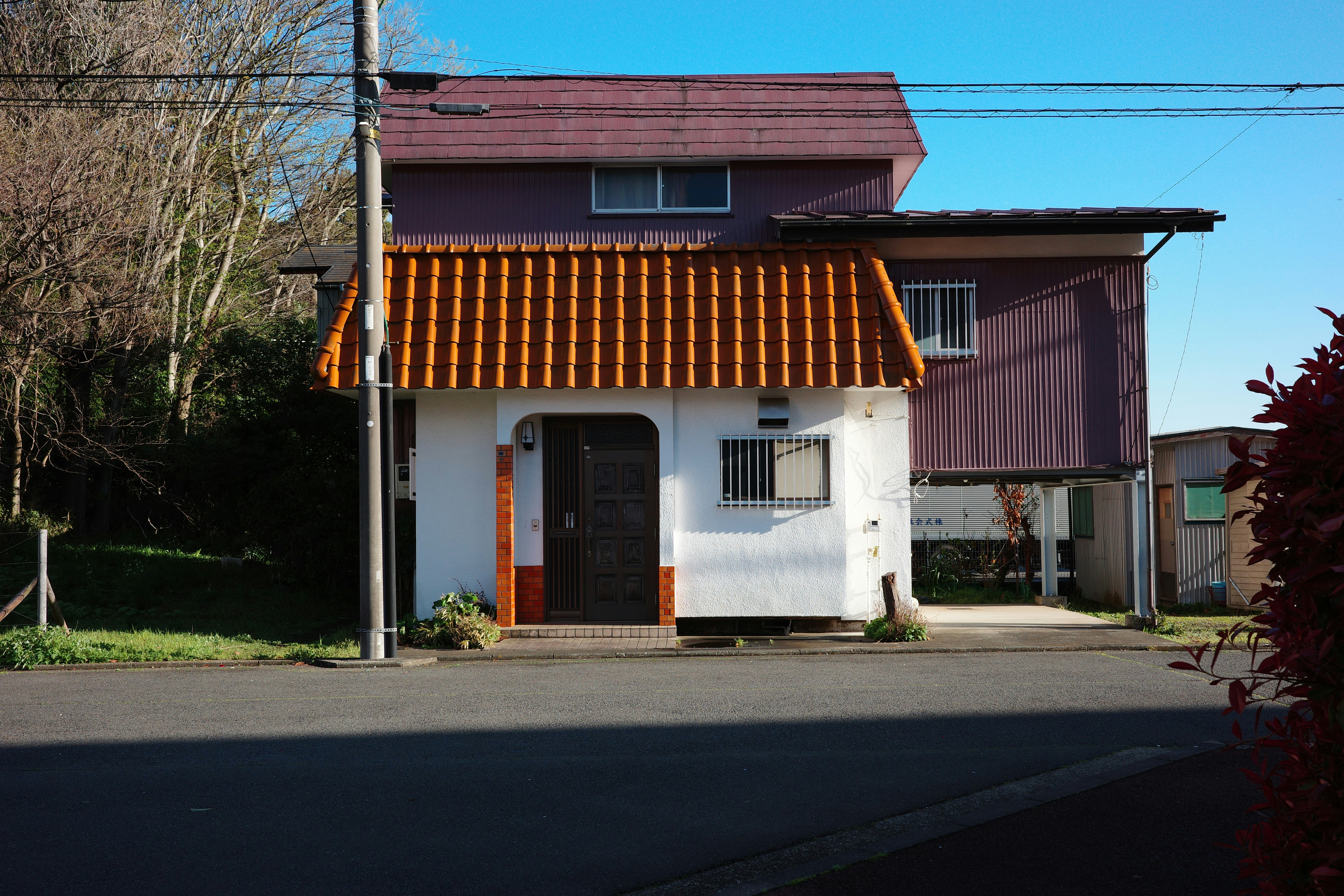 A Quiet Streetfront: White House with Orange Tile Porch Under a Blue Sky