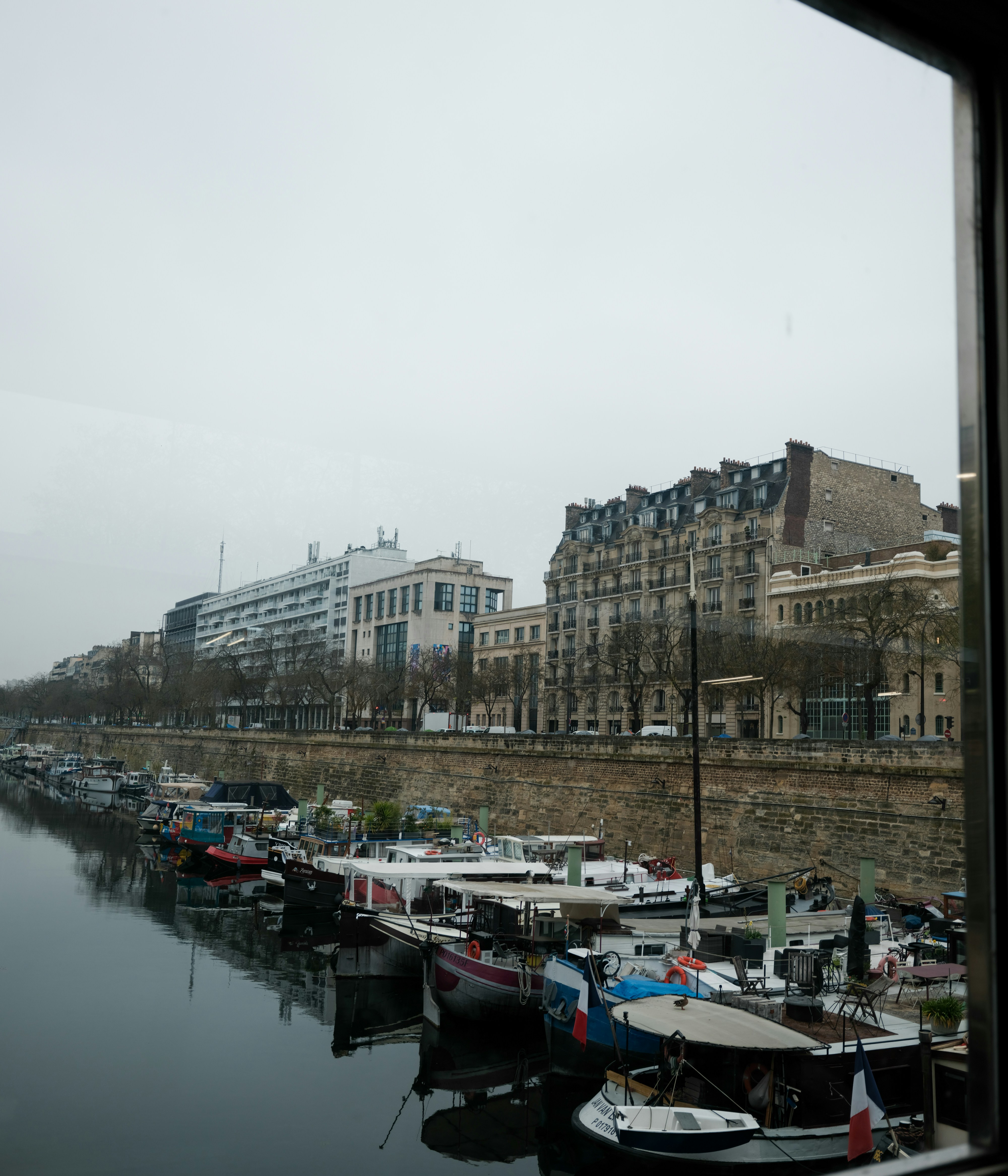 Harbor Terrace: Boats Rest Along a Quiet Riverbank Beneath Timeless City Architecture