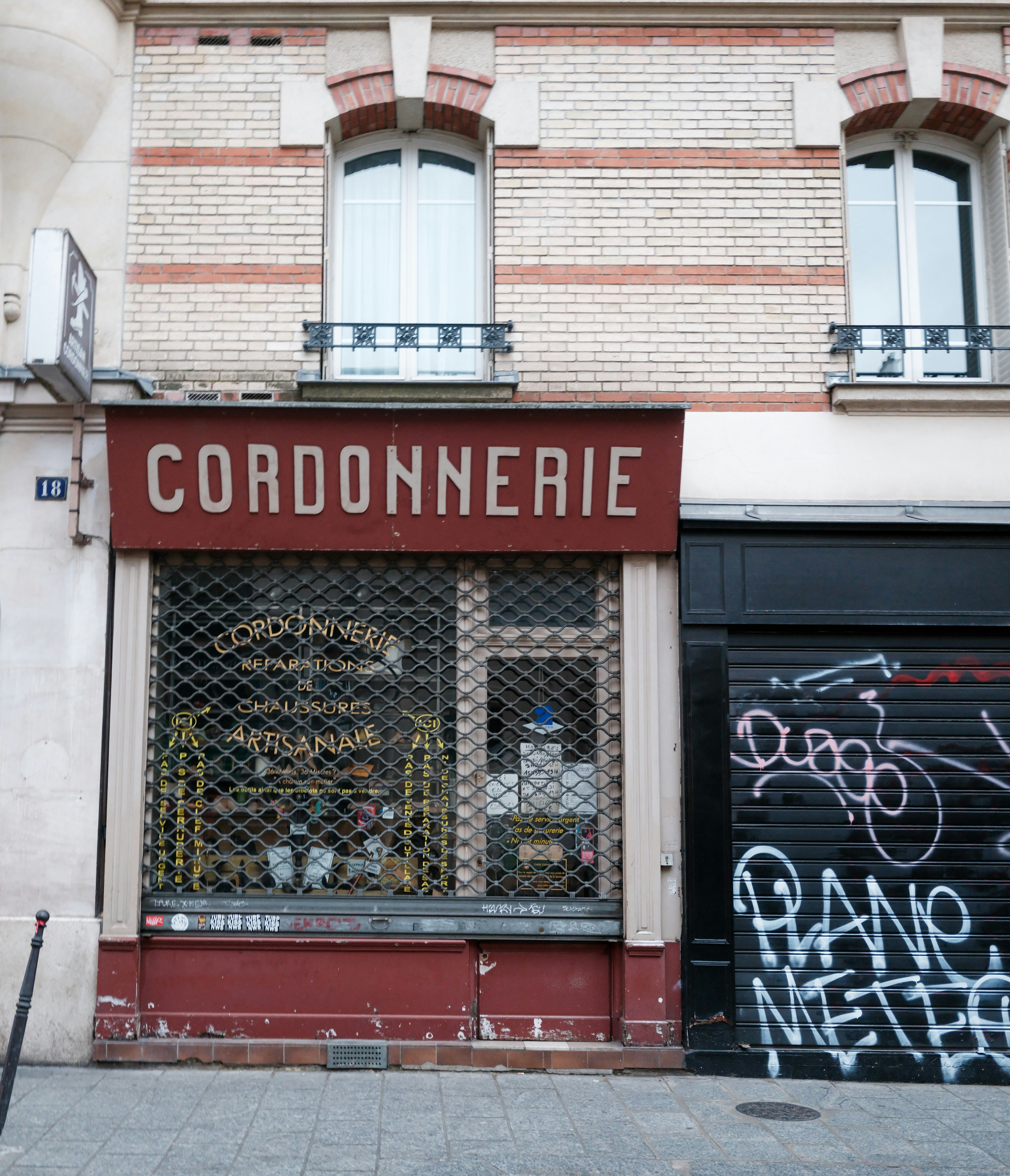 Red Signage and Industrial Grille: A Parisian Shopfront