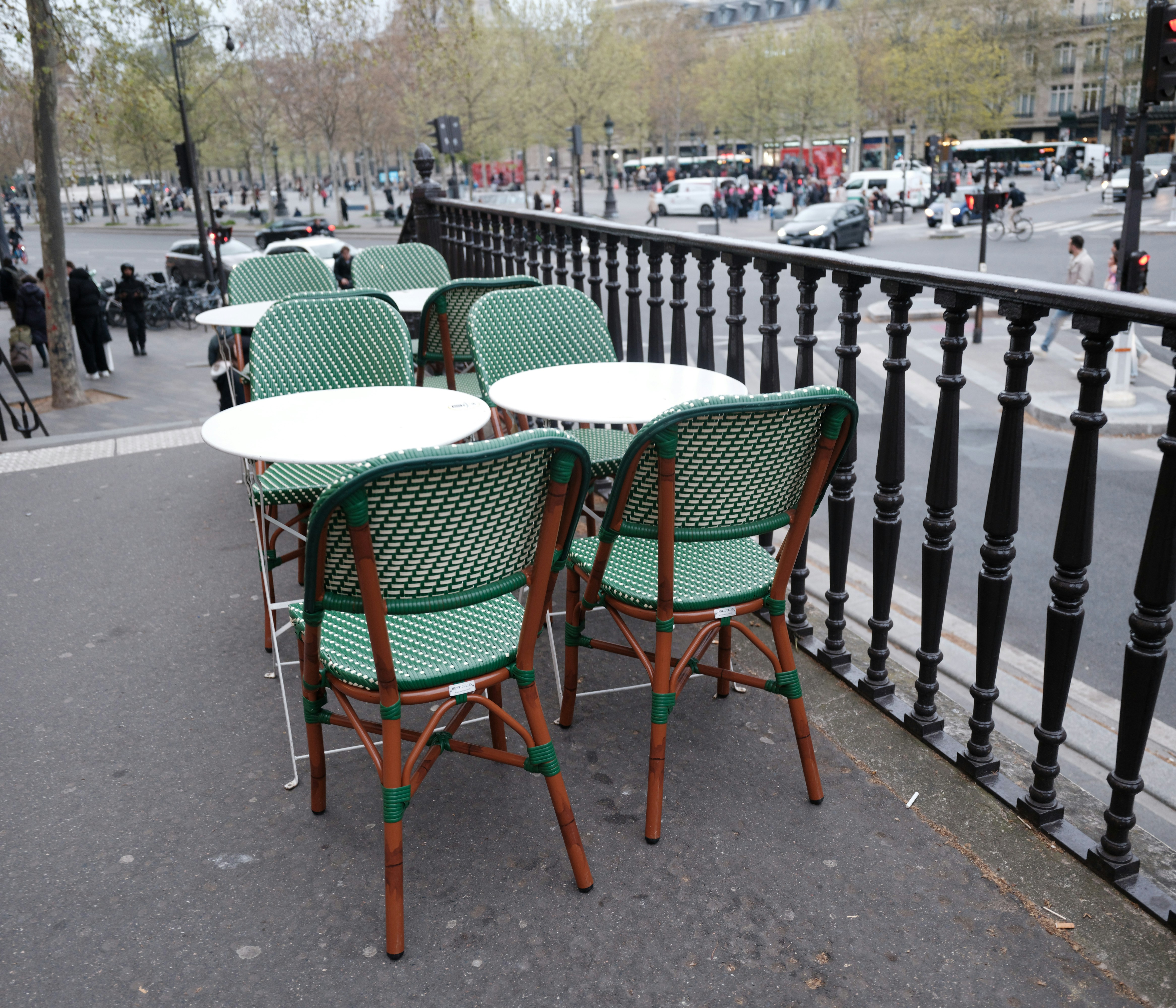 Parisian Terrace Echoes: Green Chairs and White Tables Along the Railing