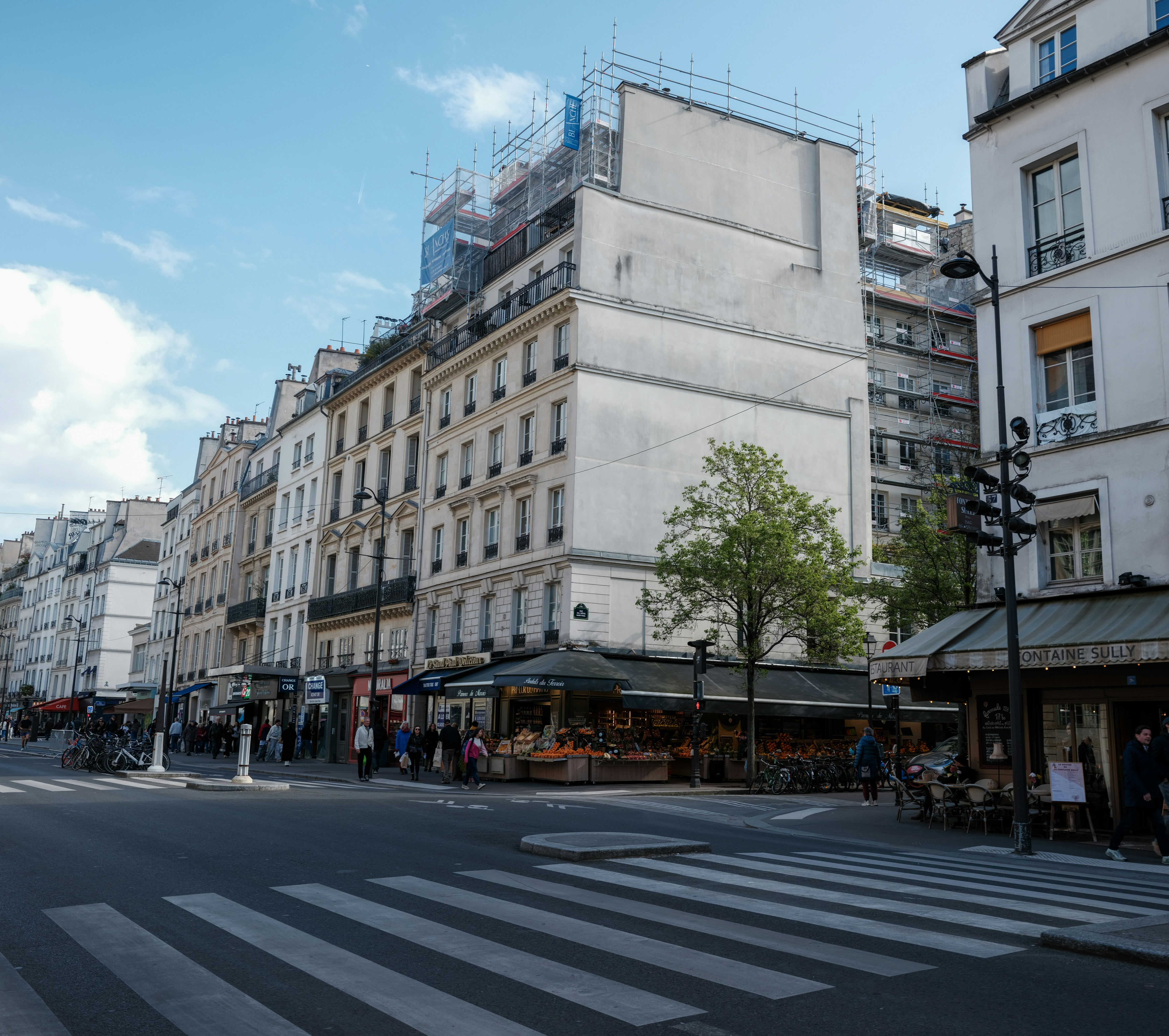 City Crossing: Pedestrians and Cafés under Pale, Scaffolding-Backed Buildings