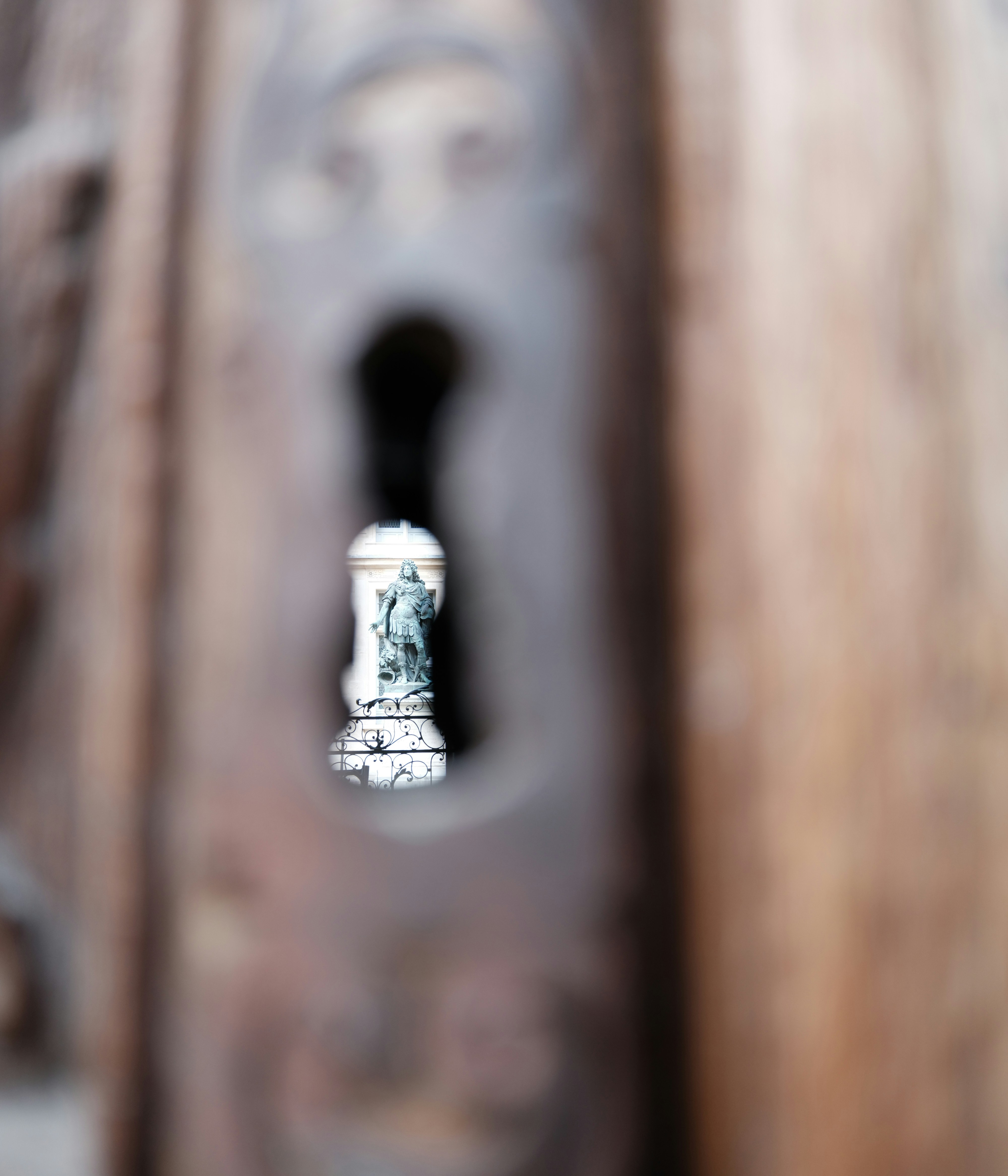 Through the Keyhole: A Statue Framed by Weathered Wood