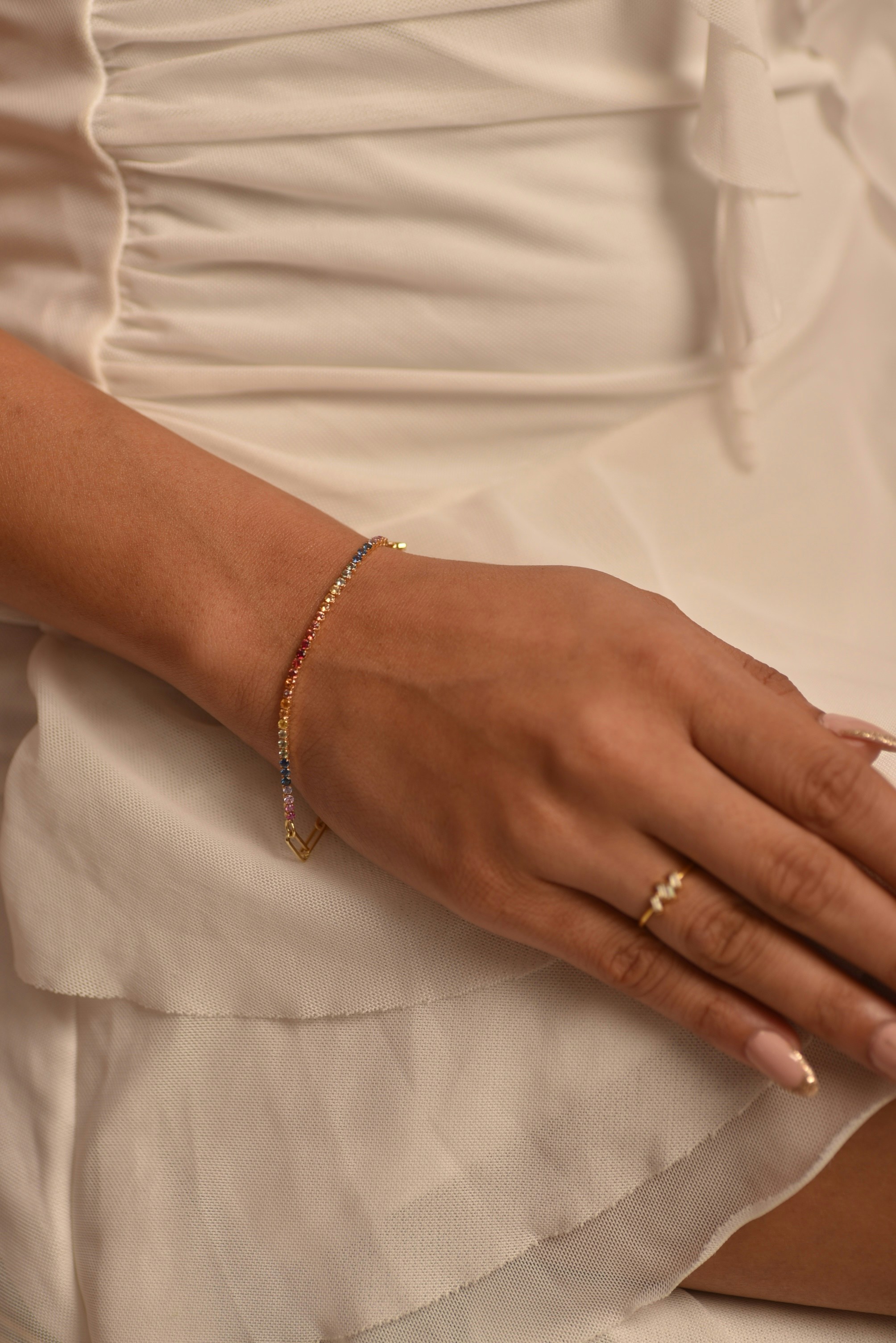 Delicate gold against ivory: a close-up of a poised hand and bracelet