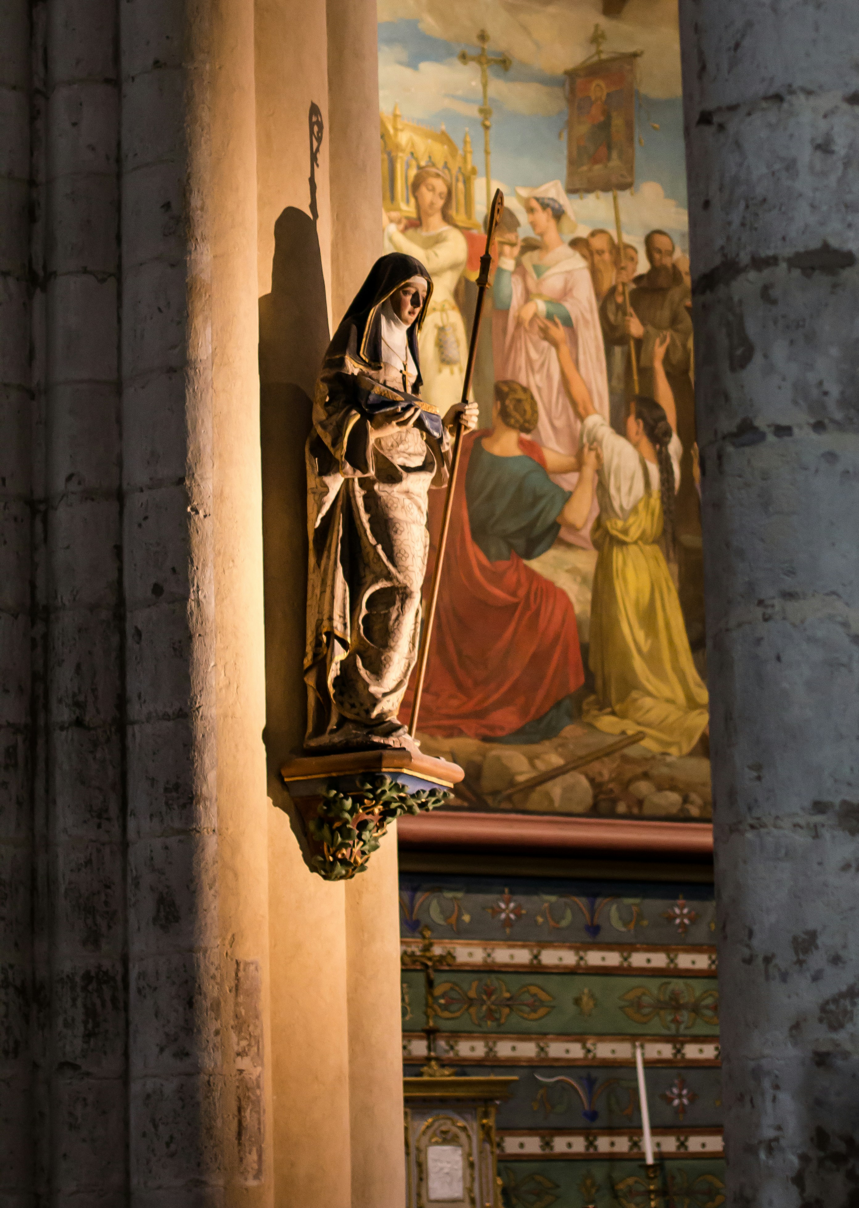 Saintly Sentinel: A Carved Figure Guarding the Painted Narrative