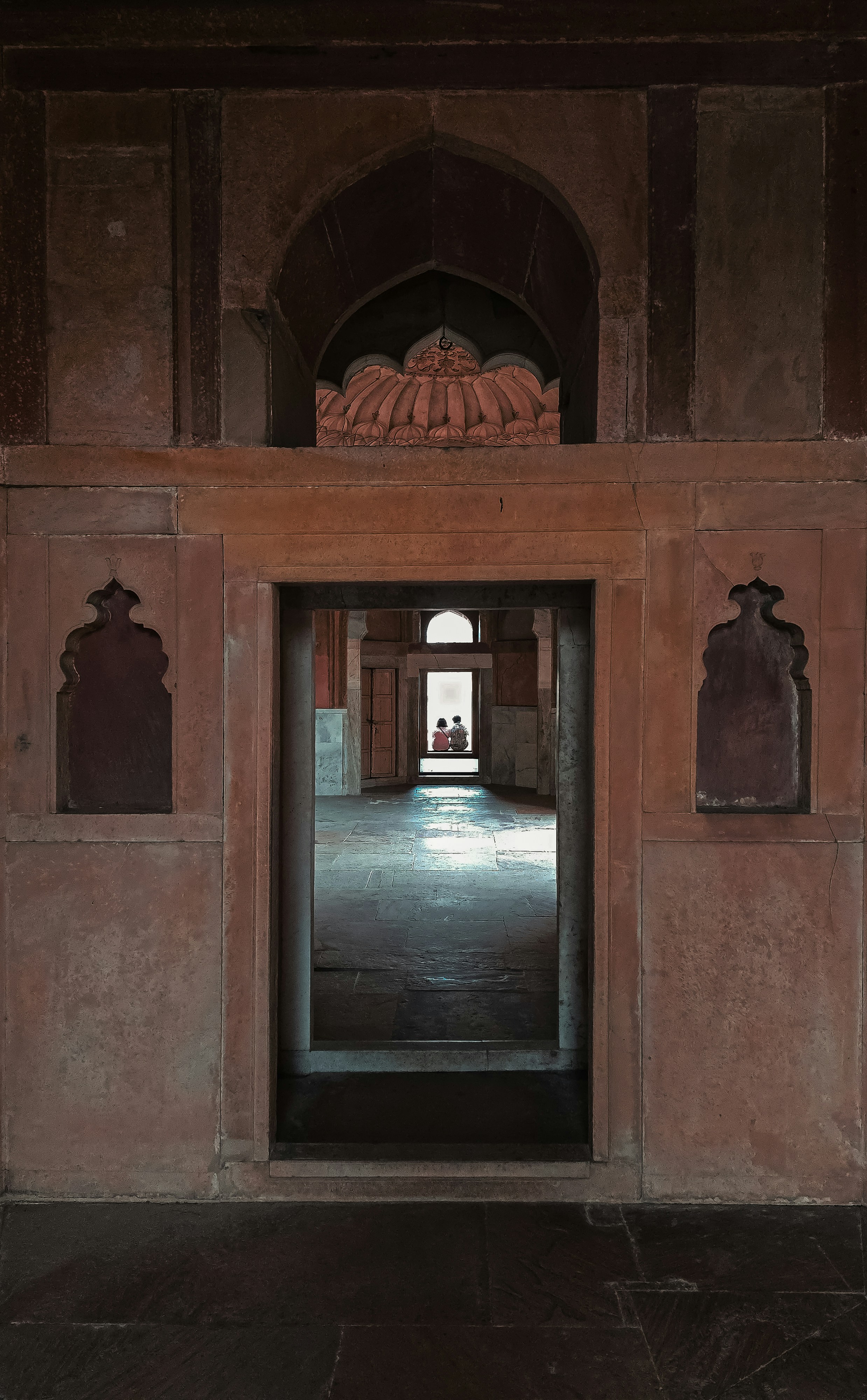 Through the Archways: A Quiet Corridor Reaches a Sunlit Corner