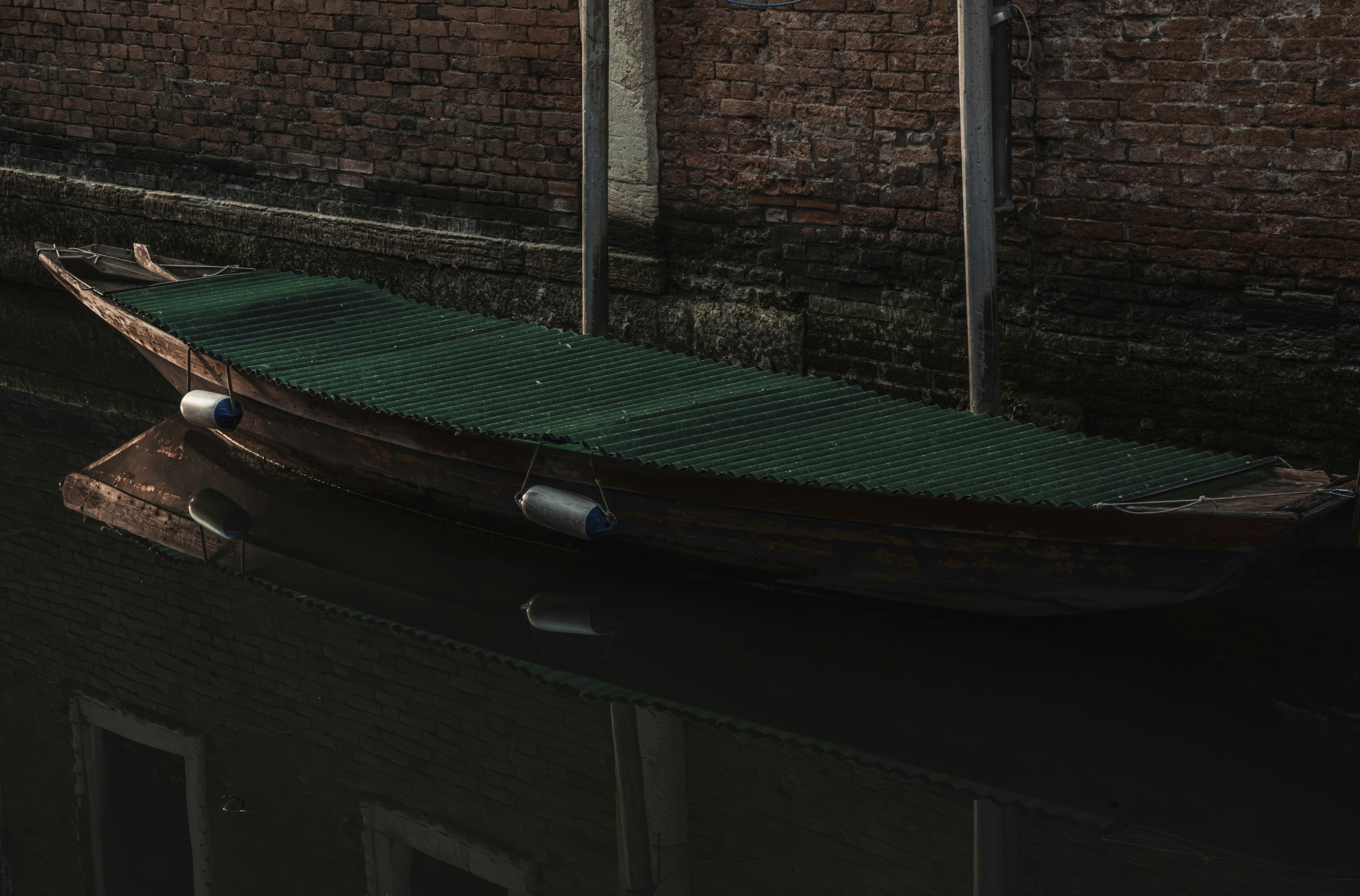 Moored in Shadow: A Narrow Boat by a Mossy Brick Wall