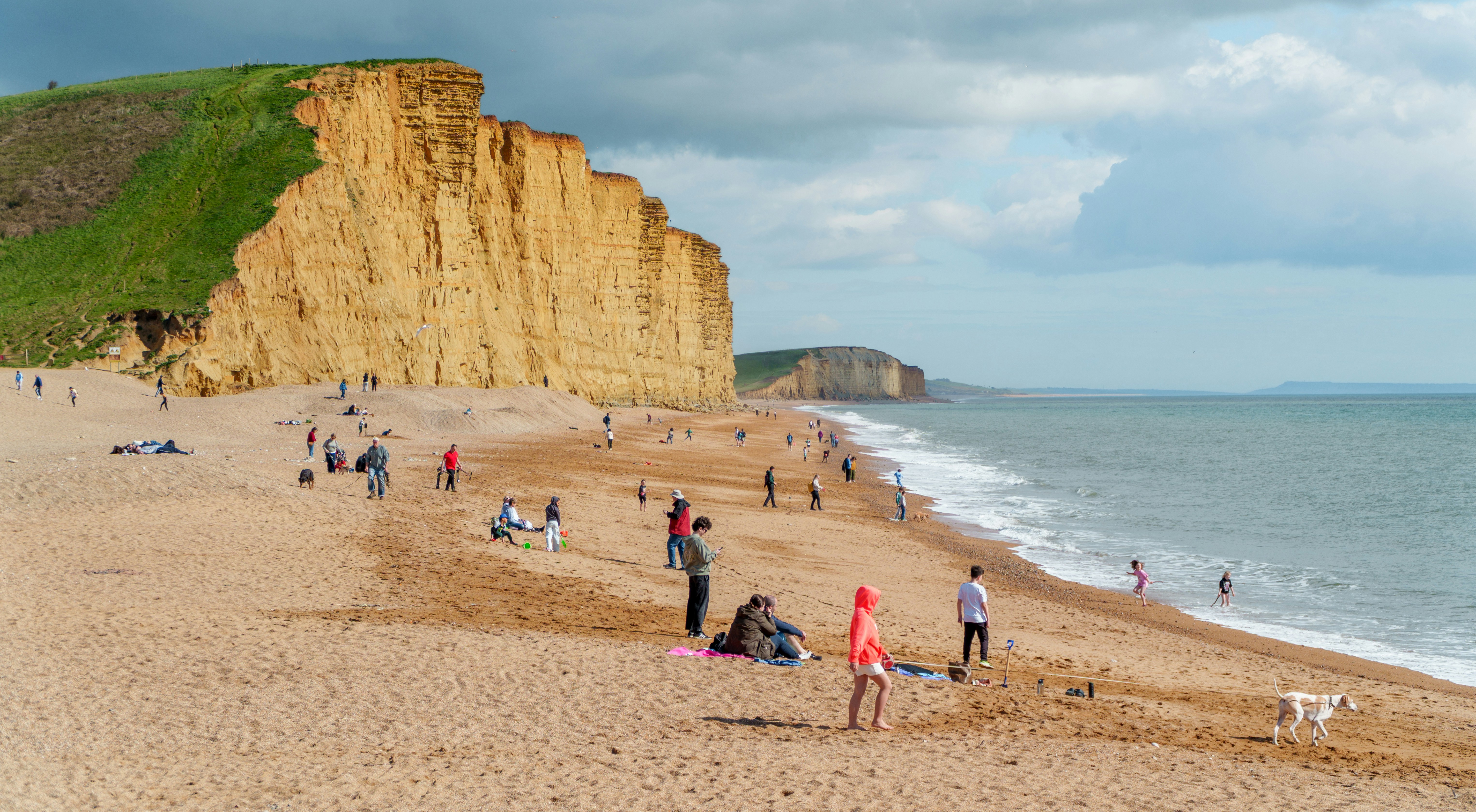 Sunlit Cliffs and Busier Shoreline: A Quiet Beach Day by the Chalky Cliffs