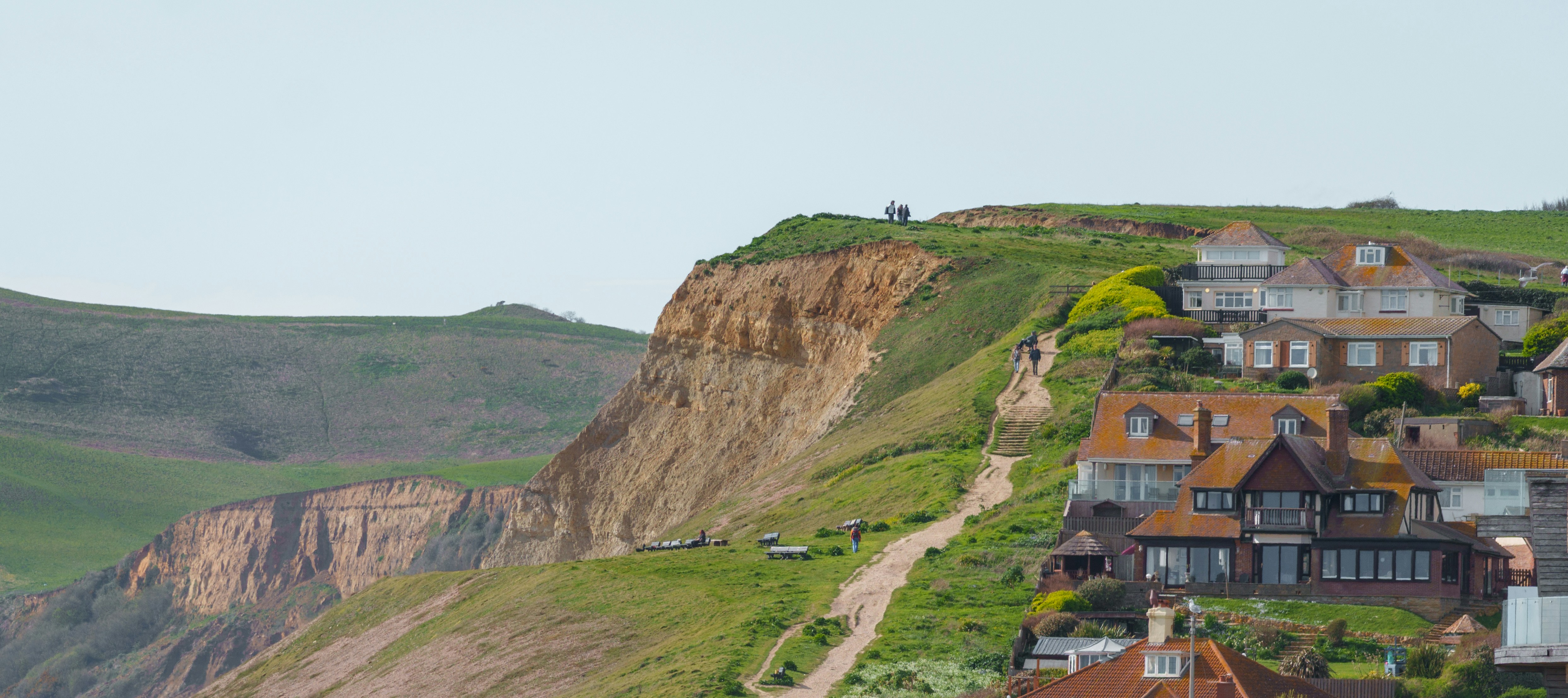 Coastal Village Crest: Houses cling to the Cliffs Above a Wind-Washed Path