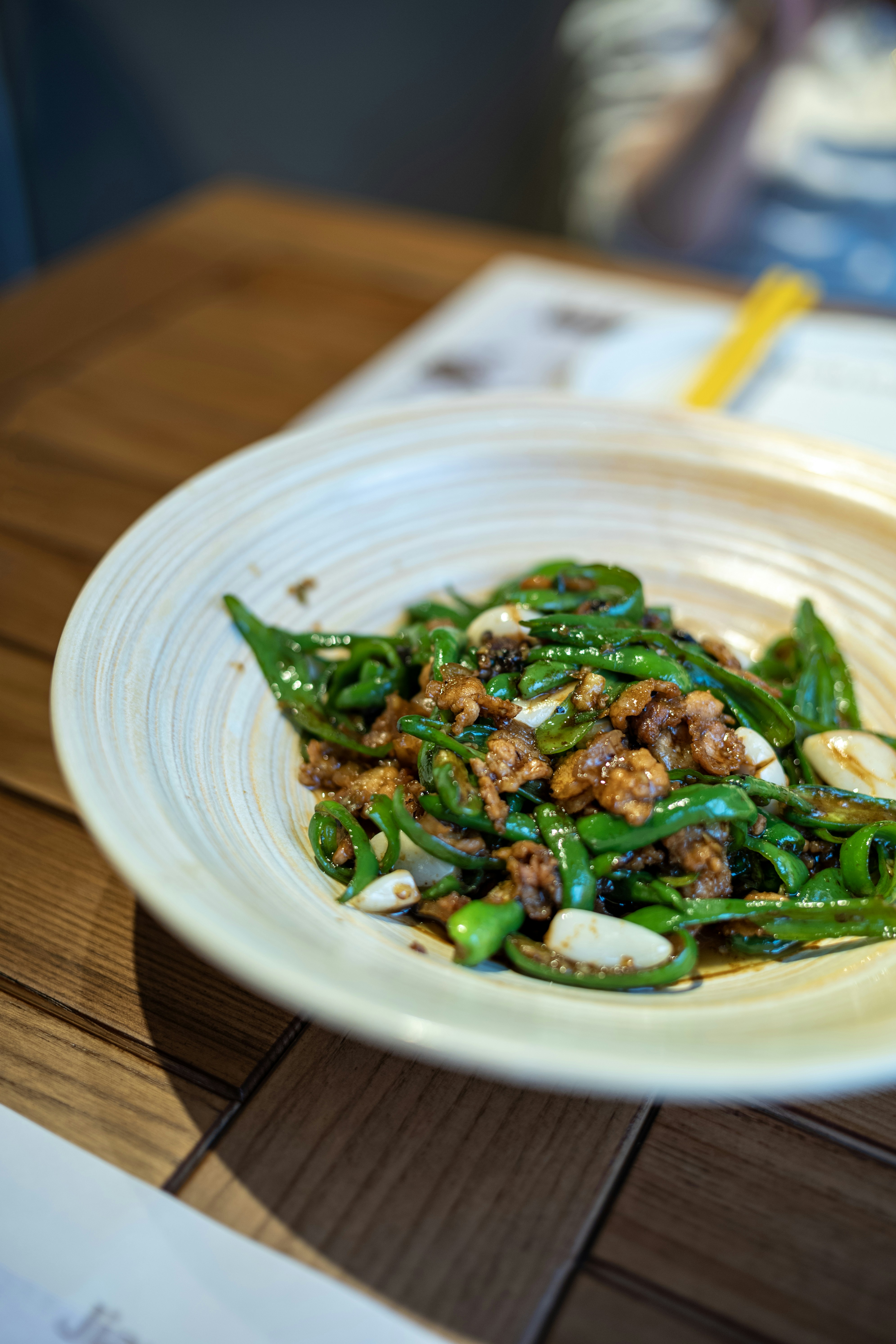 Stir-Fry Symphony: Green Beans, Onions, and Crispy Meat in a Shallow Bowl
