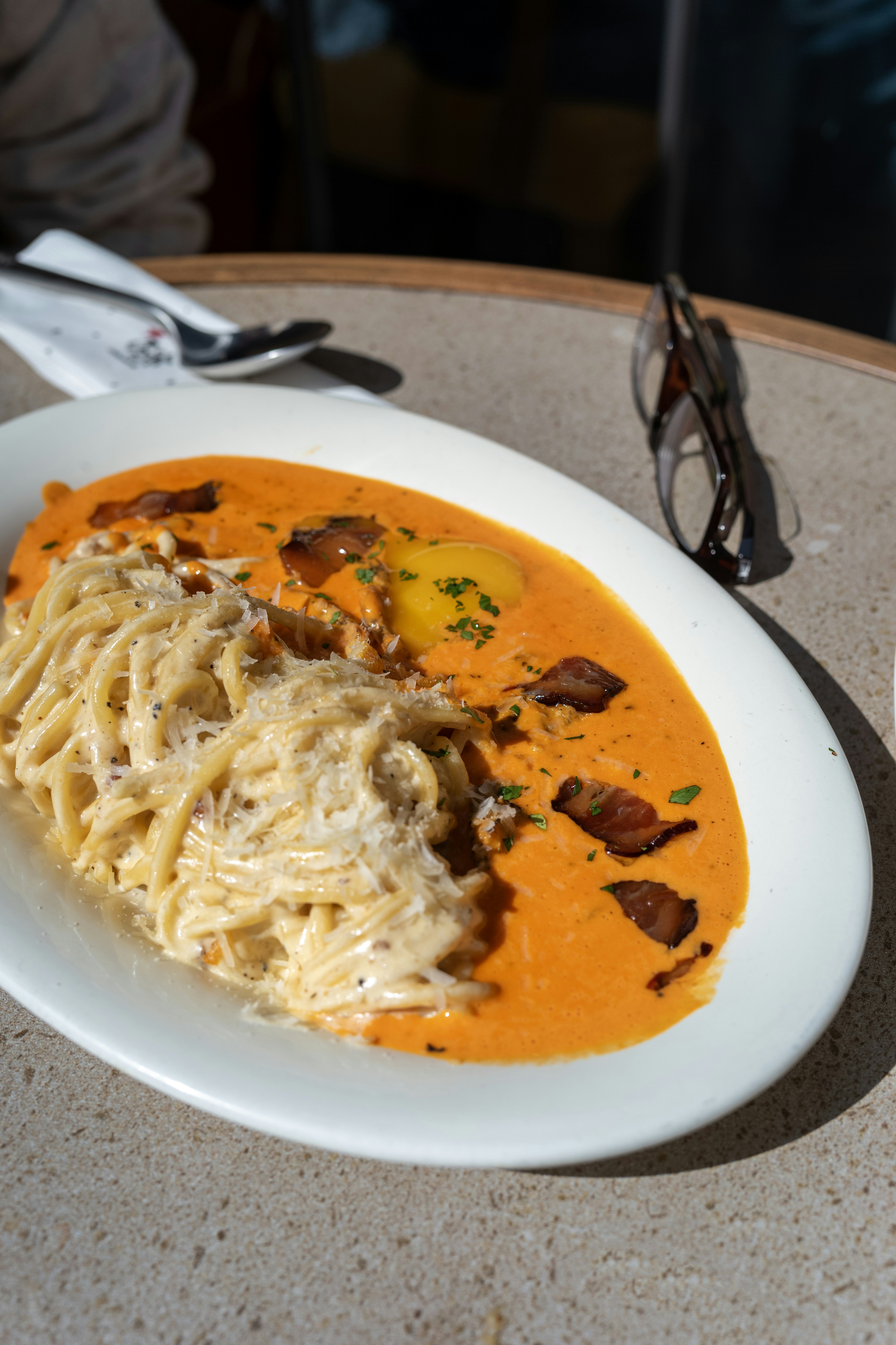 Creamy orange-tinted sauce cloaks a pasta dish, with a ribbon of al dente noodles resting on a white plate