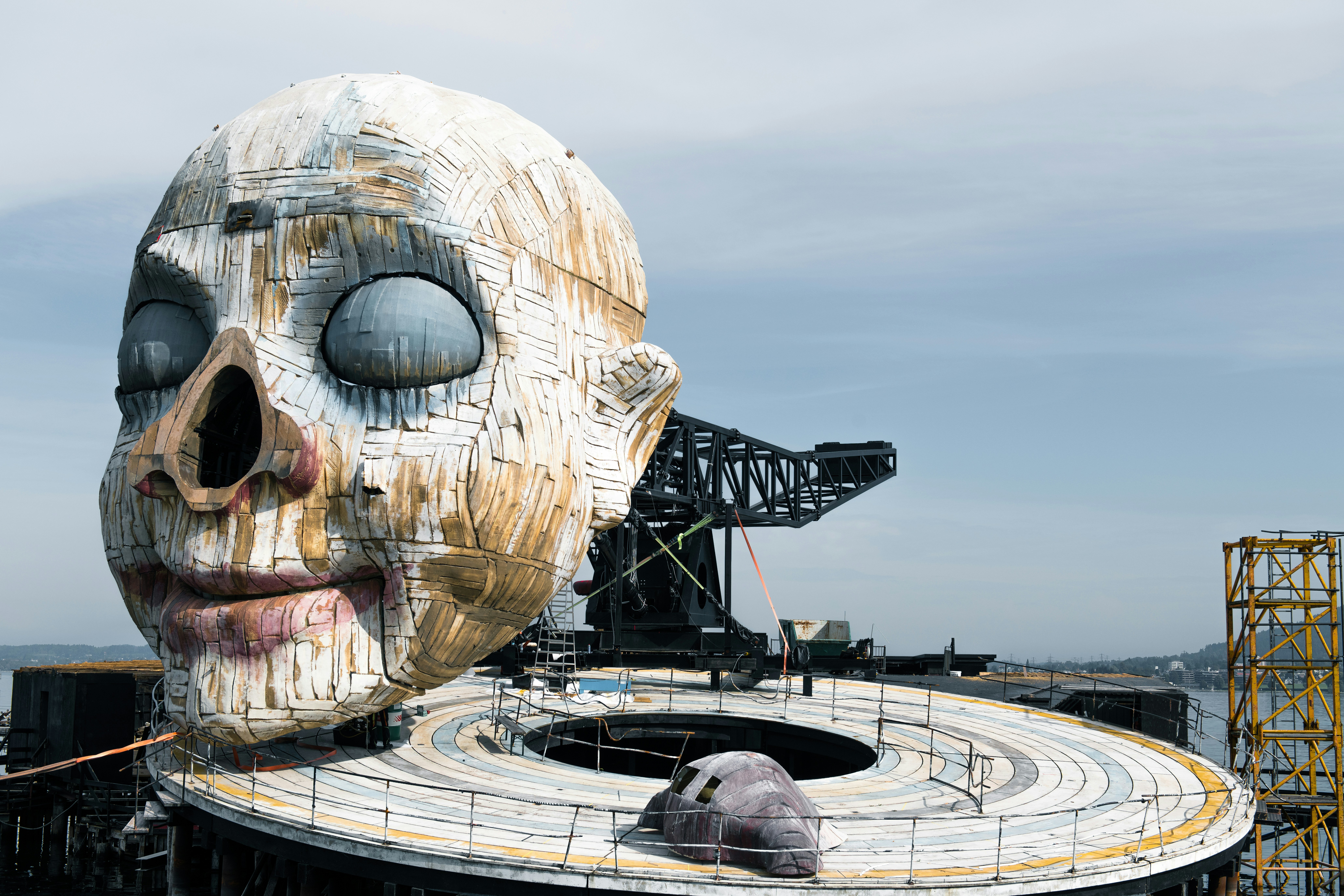Giant Puppet Head Rises from a Circular Construction Platform