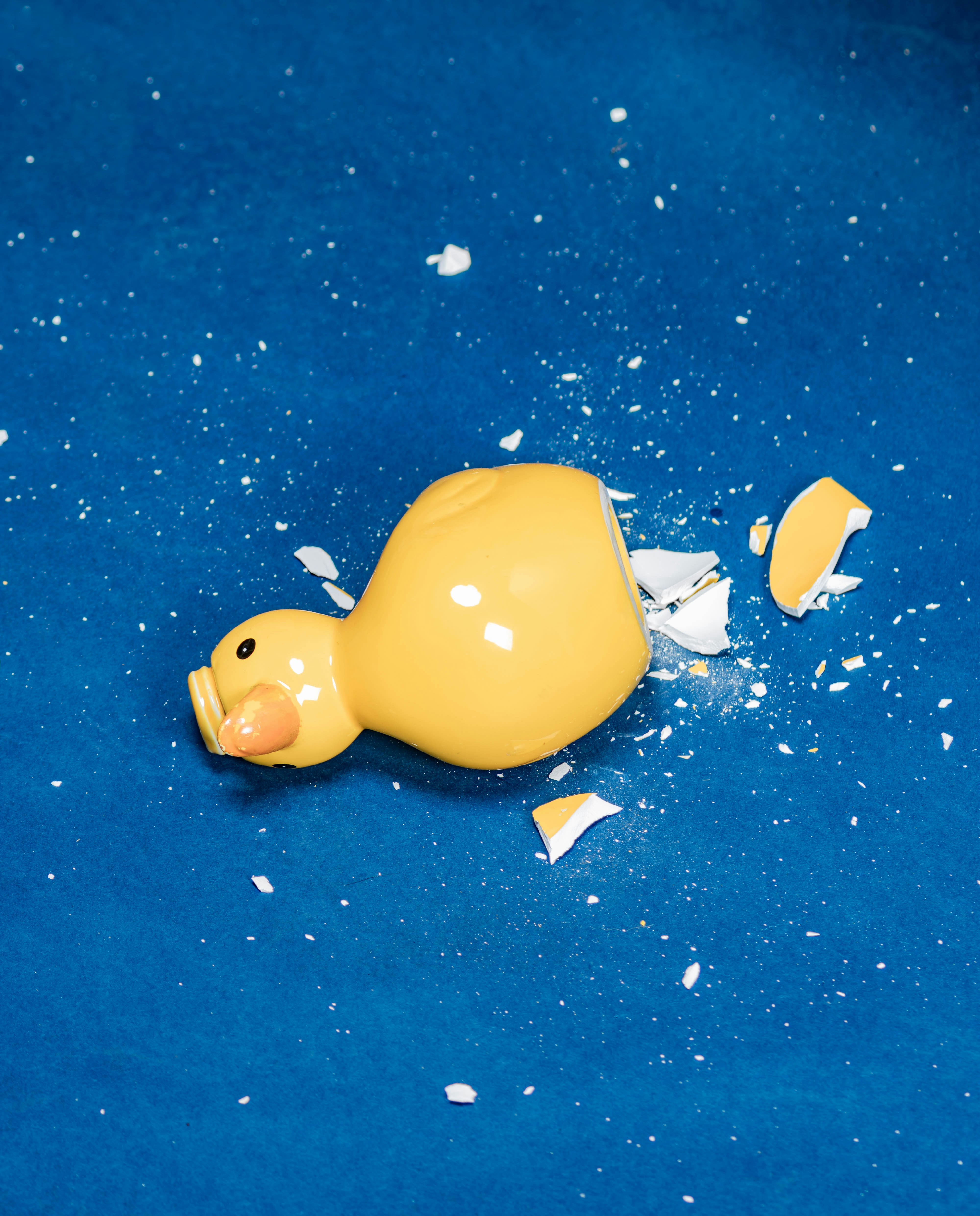 Cracked Yellow Duck: Shattered Cheer on a Blue Surface