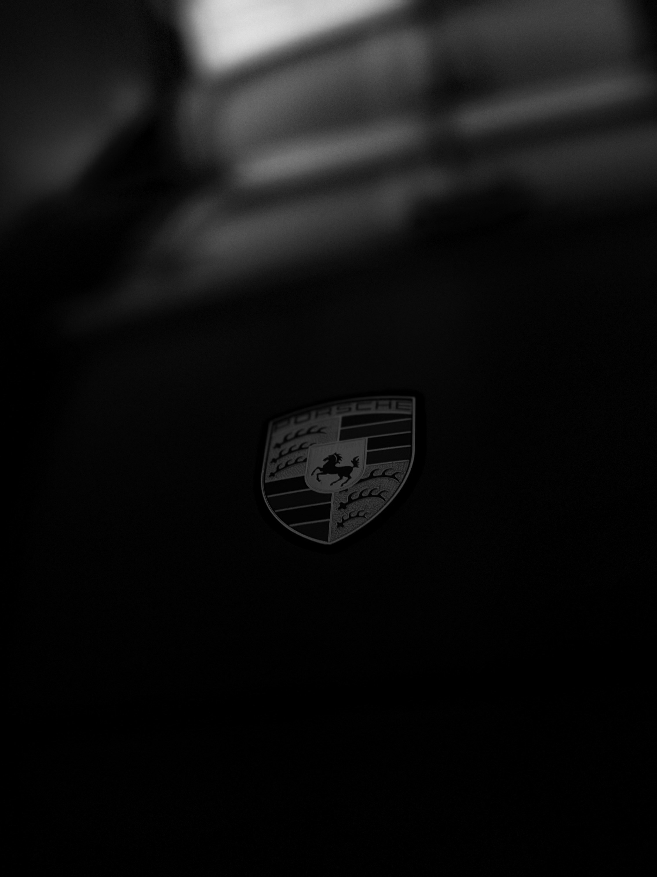 Emblem in the Dark: Porsche Crest Emerges from Shadow