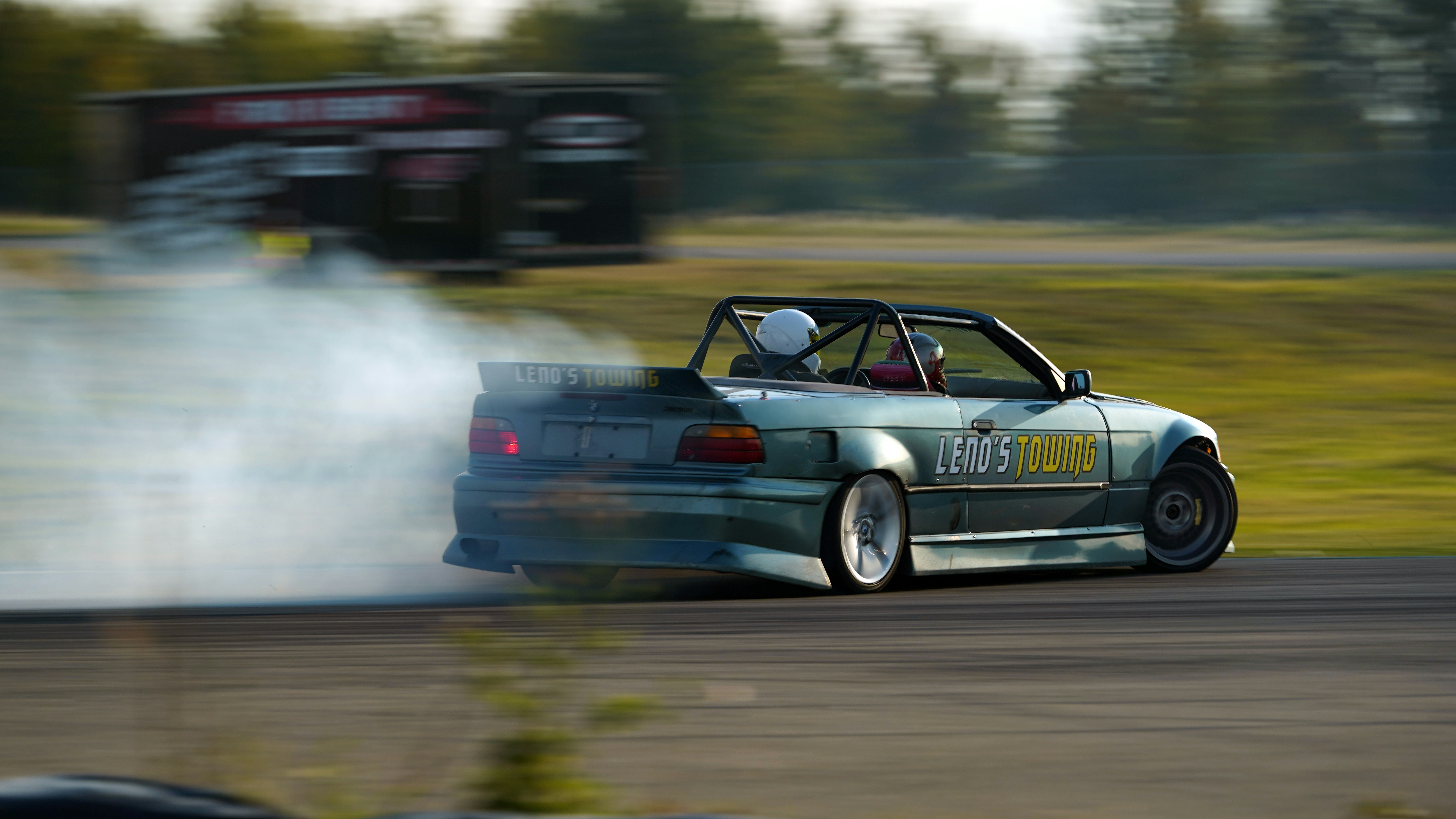 Blue drift car powers through smoke on sunlit track