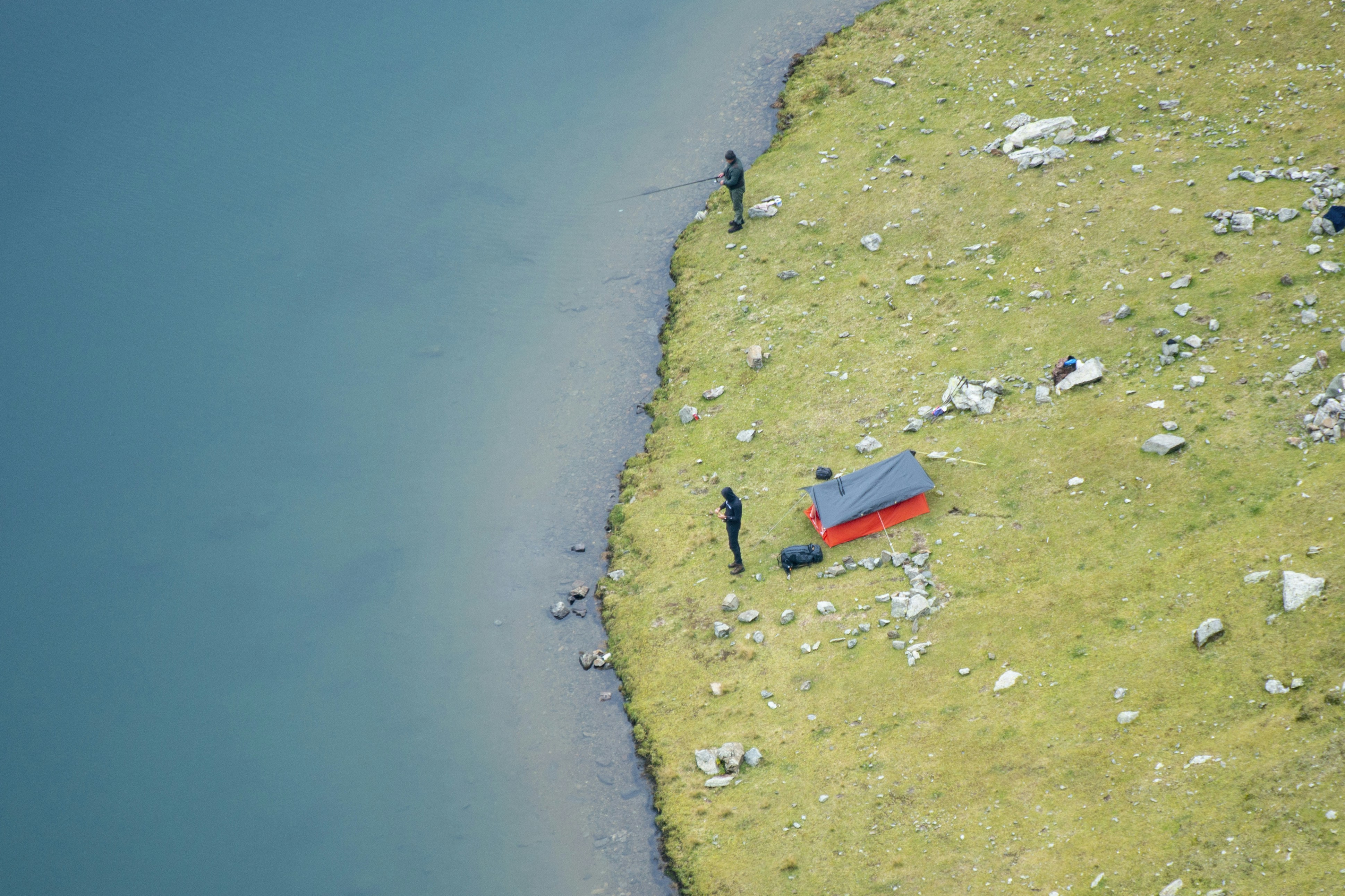 Tents, Tranquil Shoreline, and Pale Hillside by a Quiet Fjord