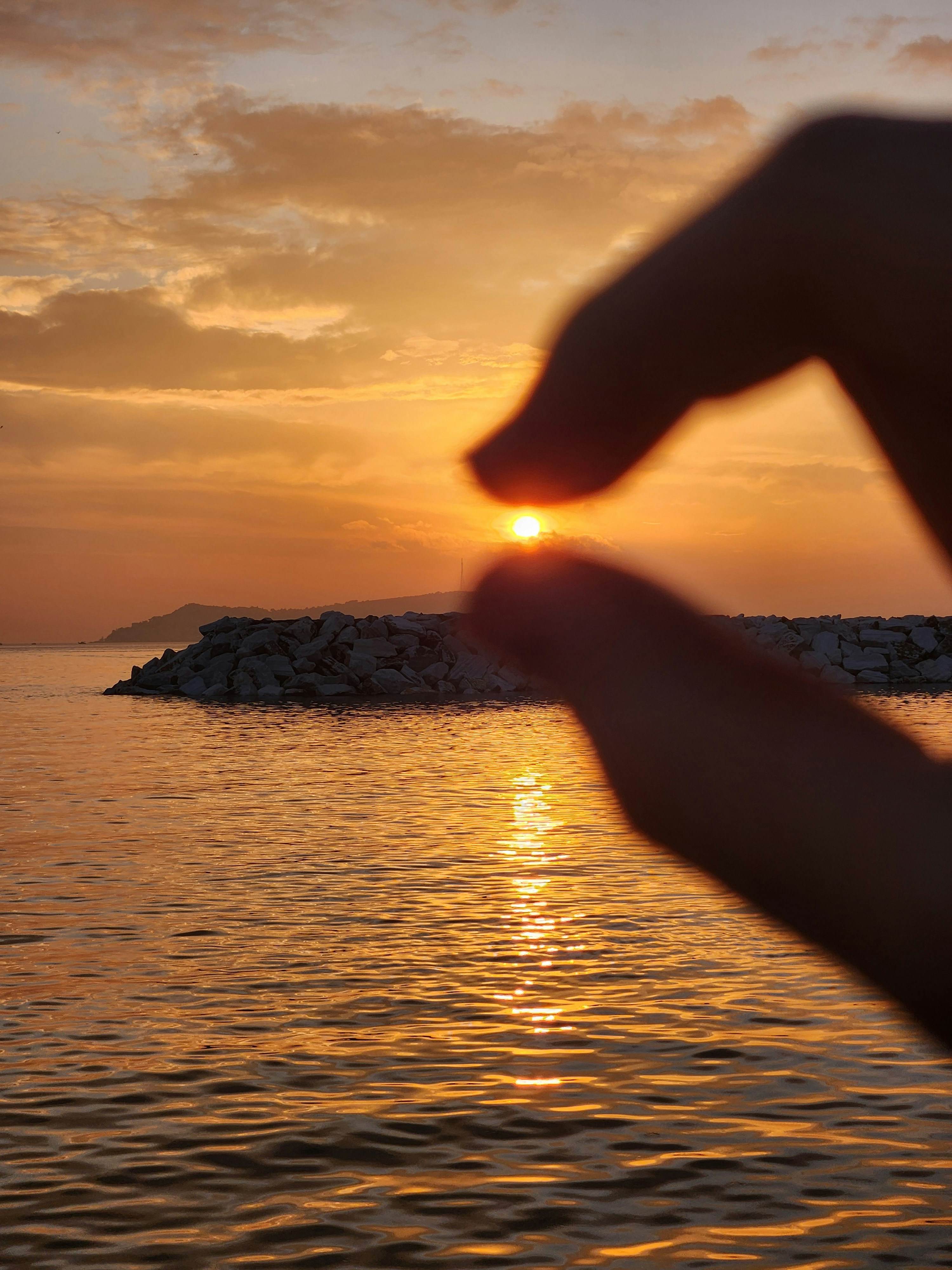 Holding the Sun: a playful horizon framed by fingers