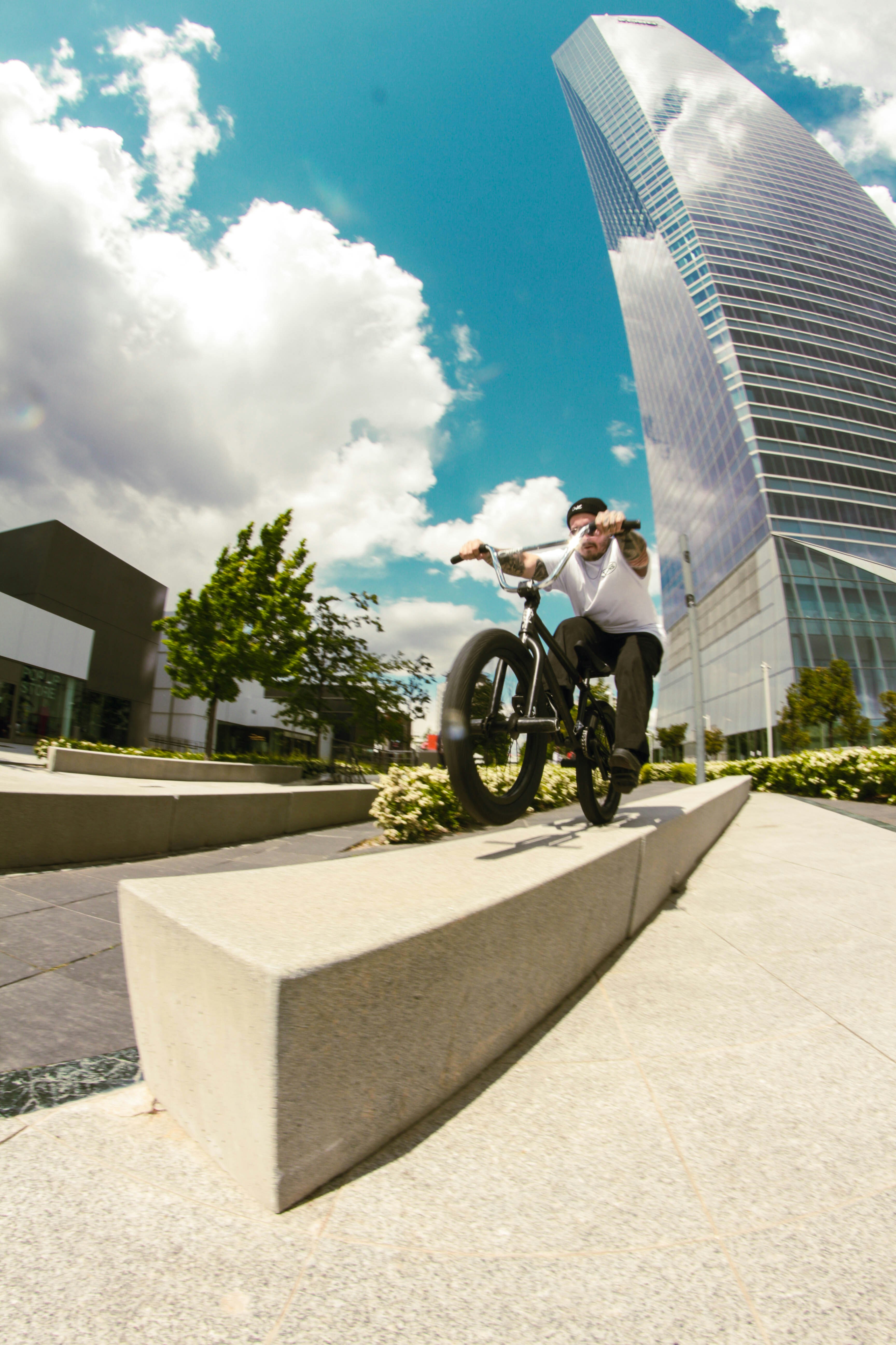 Cyclist Defying Gravity on a Concrete Beam Beneath a Towering Skyline