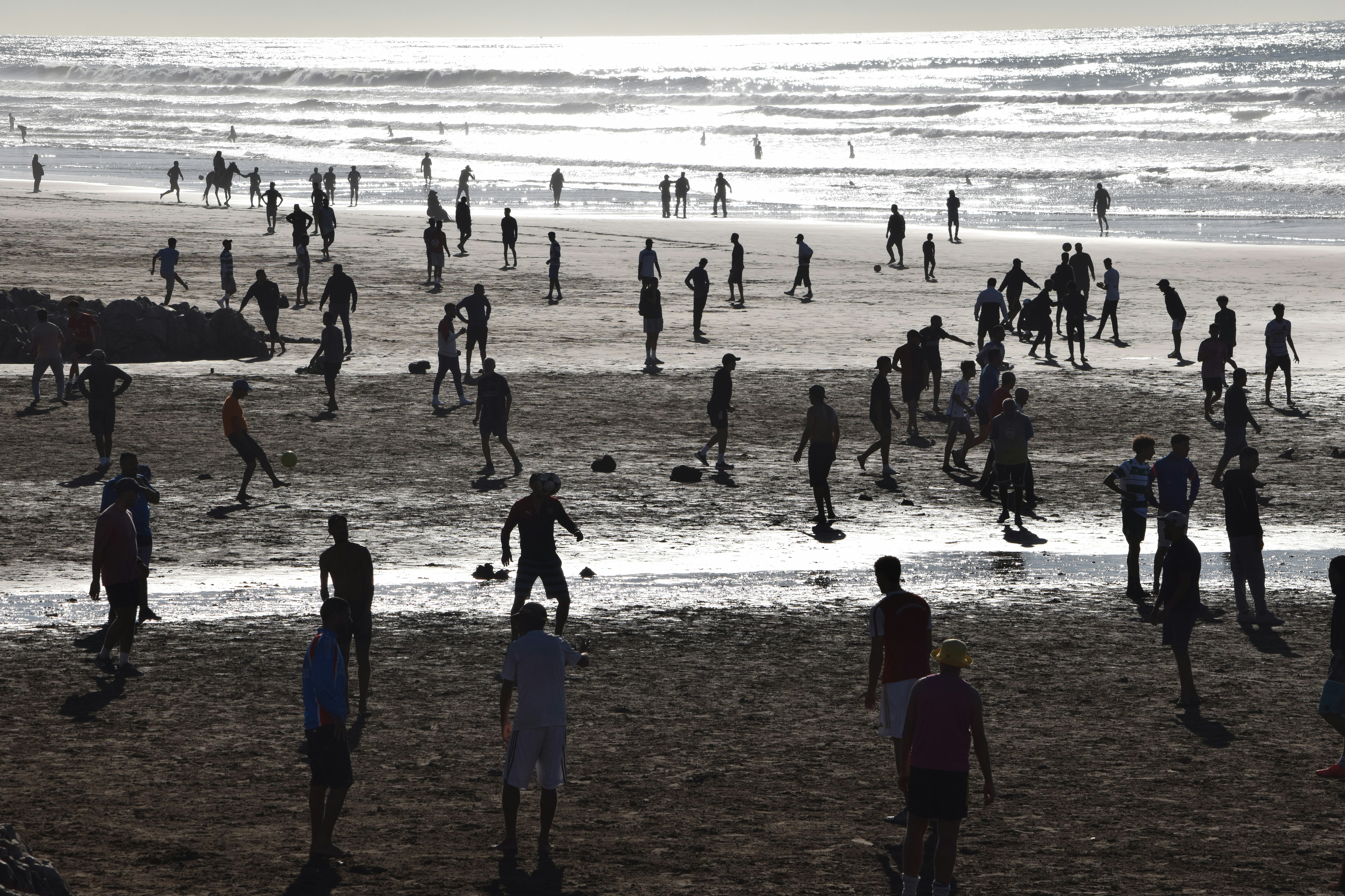 Sunlit silhouettes: crowded shoreline under a shimmering sea